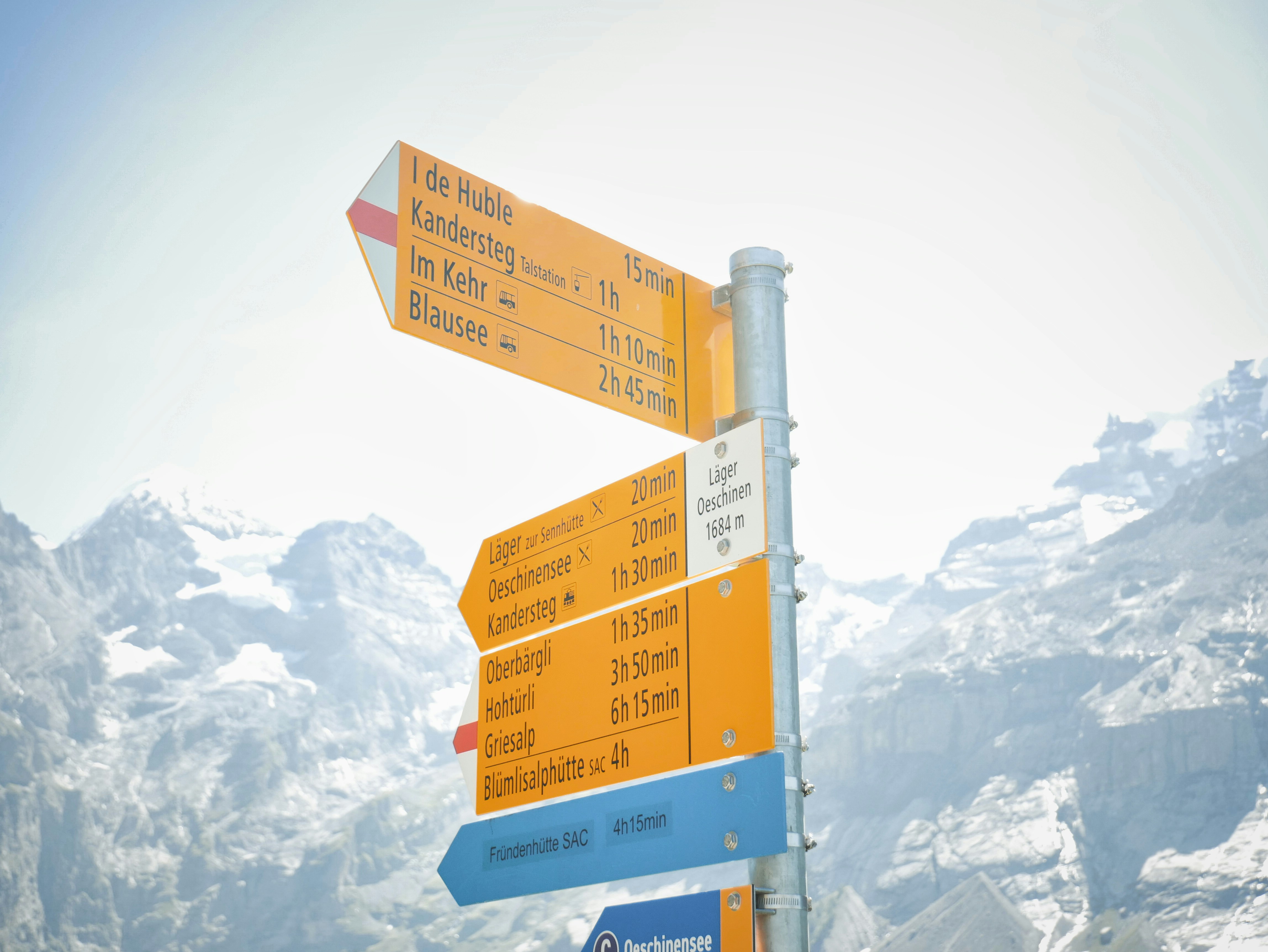 Radiant Alpine Signpost: Trails Amid Snowy Giants