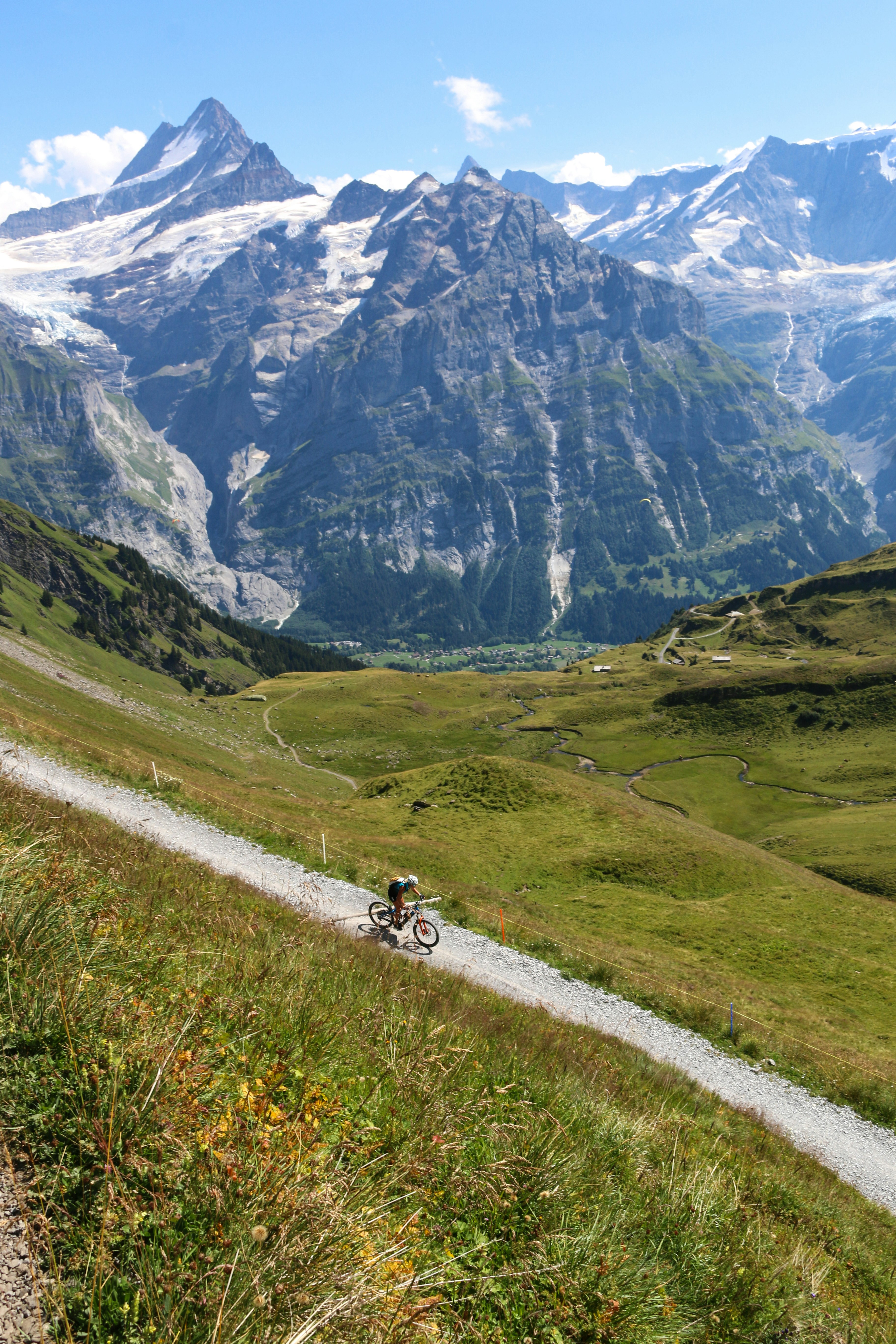 Ridge Descent: A lone cyclist against a soaring Alpine panorama