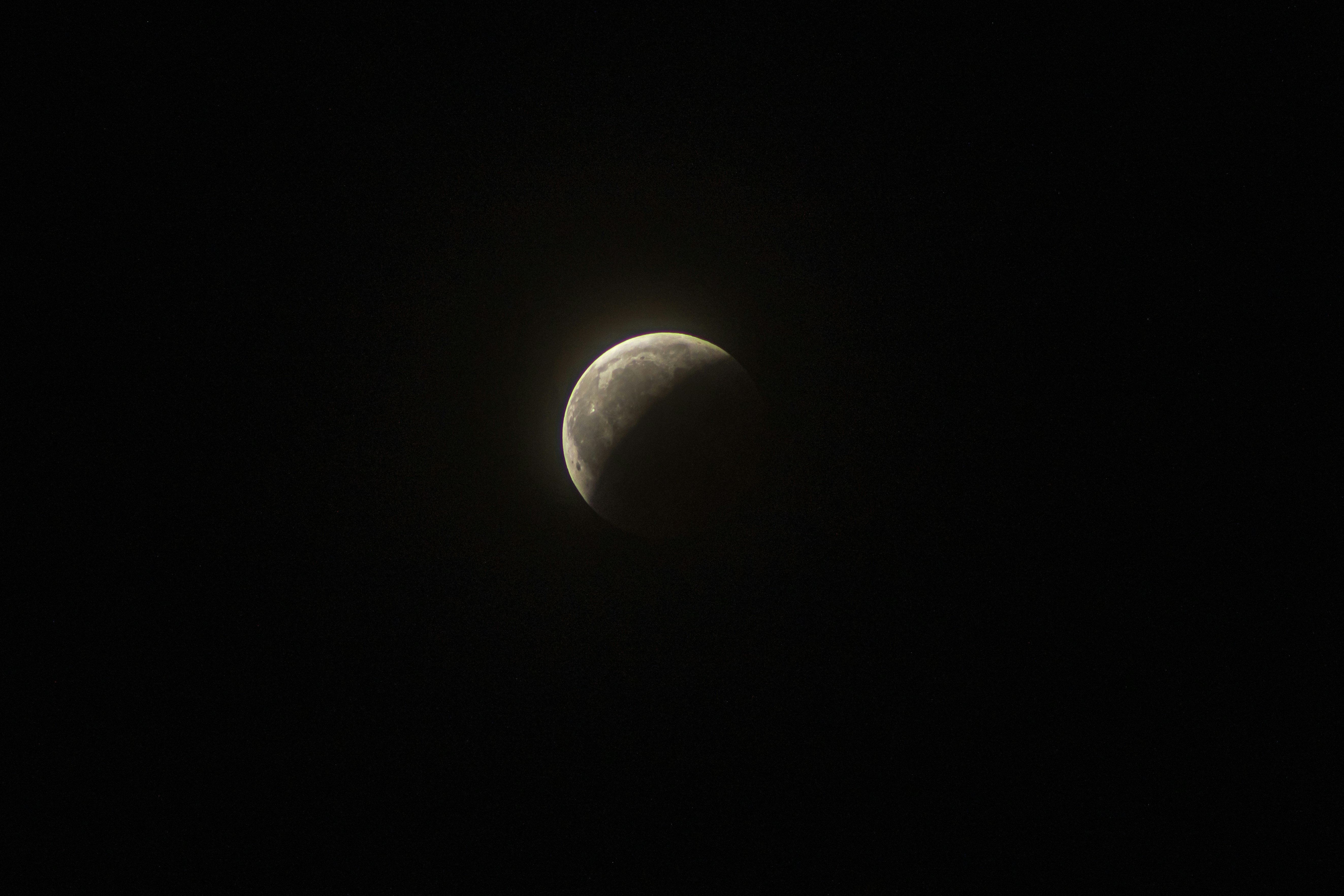 Slim crescent moon softly illuminated against deep night sky, with subtle earthshine visible along the lunar limb.