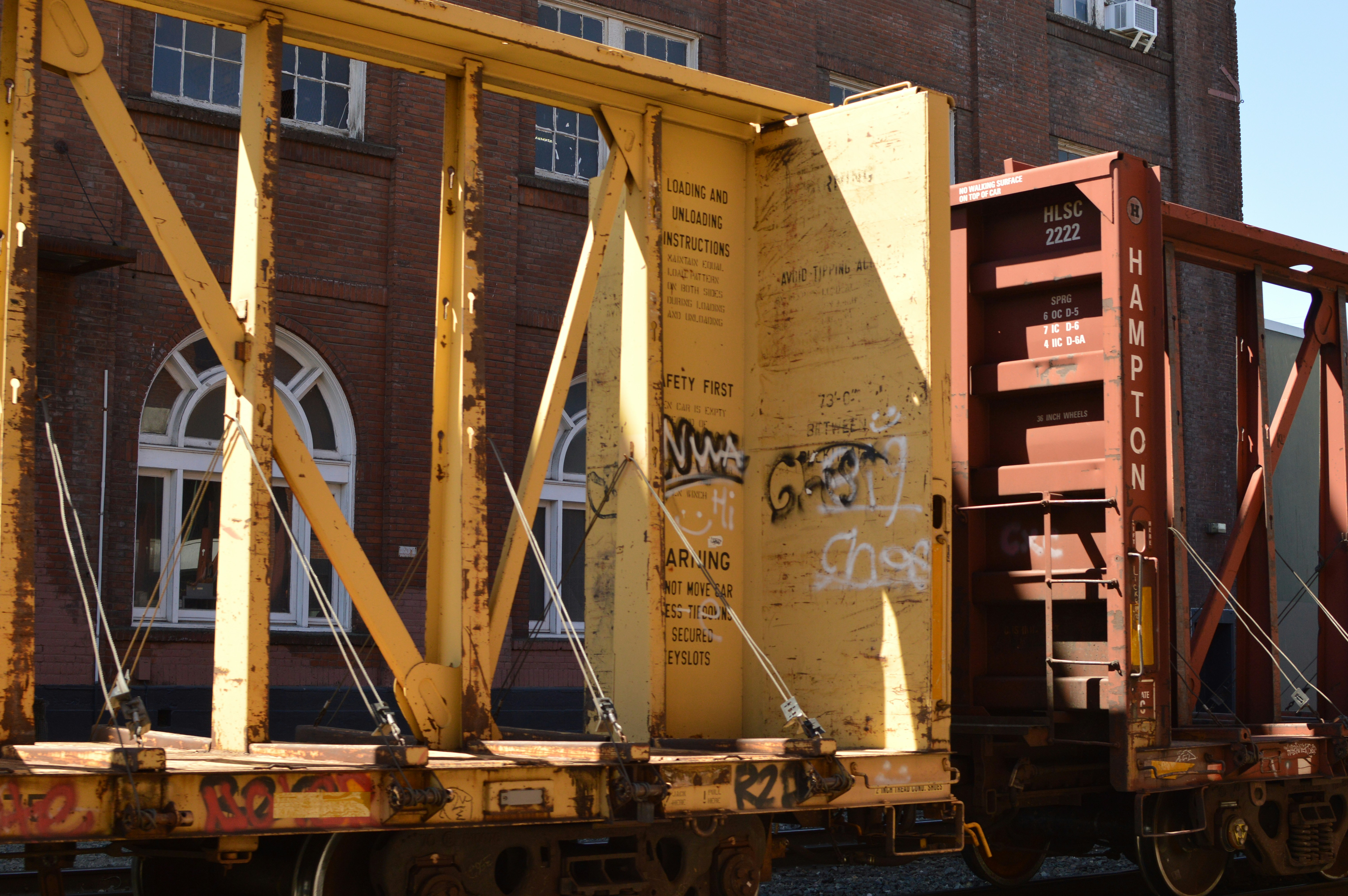 Weathered freight car under urban yellow framework against brick building