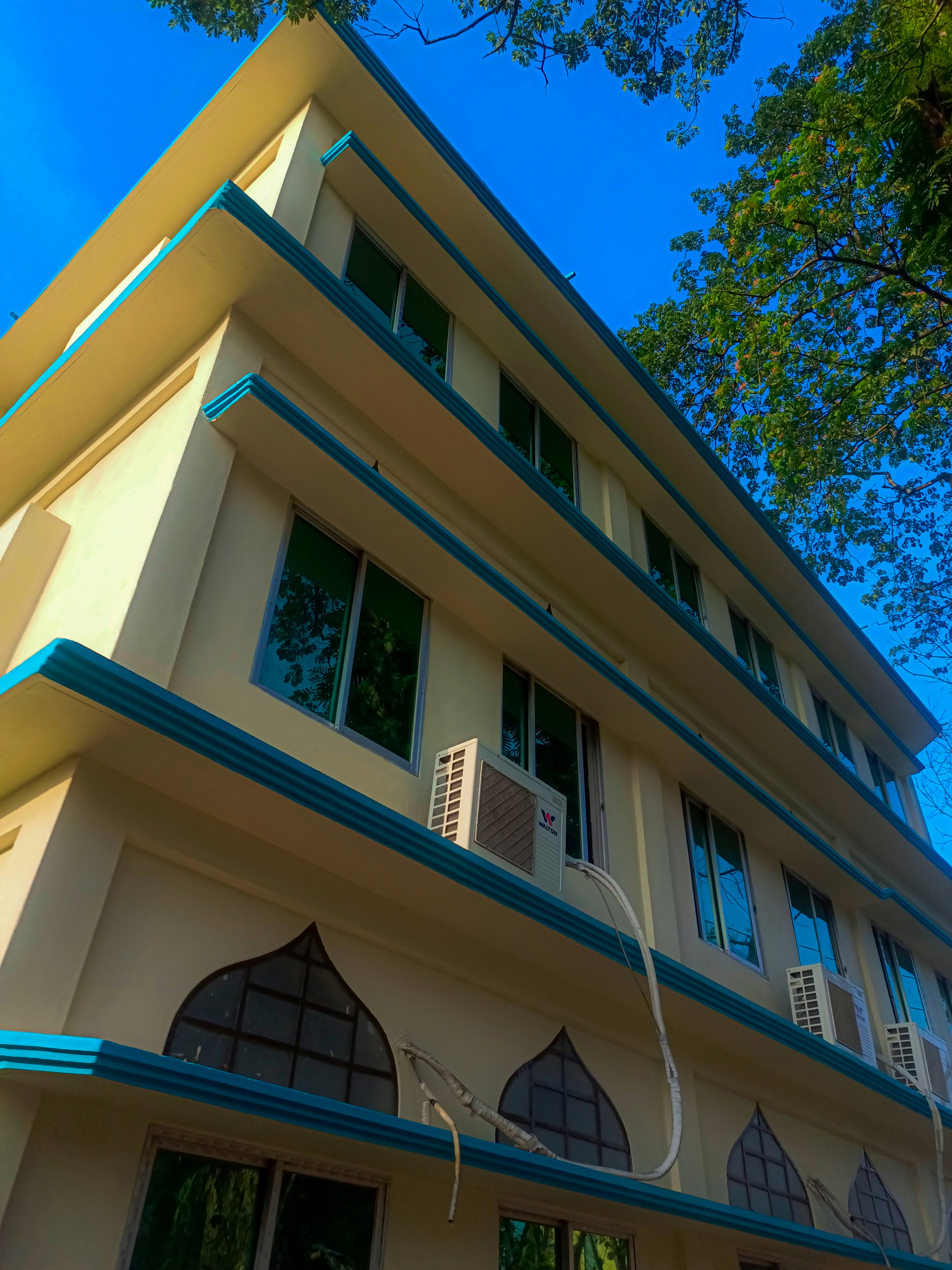 Angle of daylight: a sunlit modern facade rising toward a blue sky