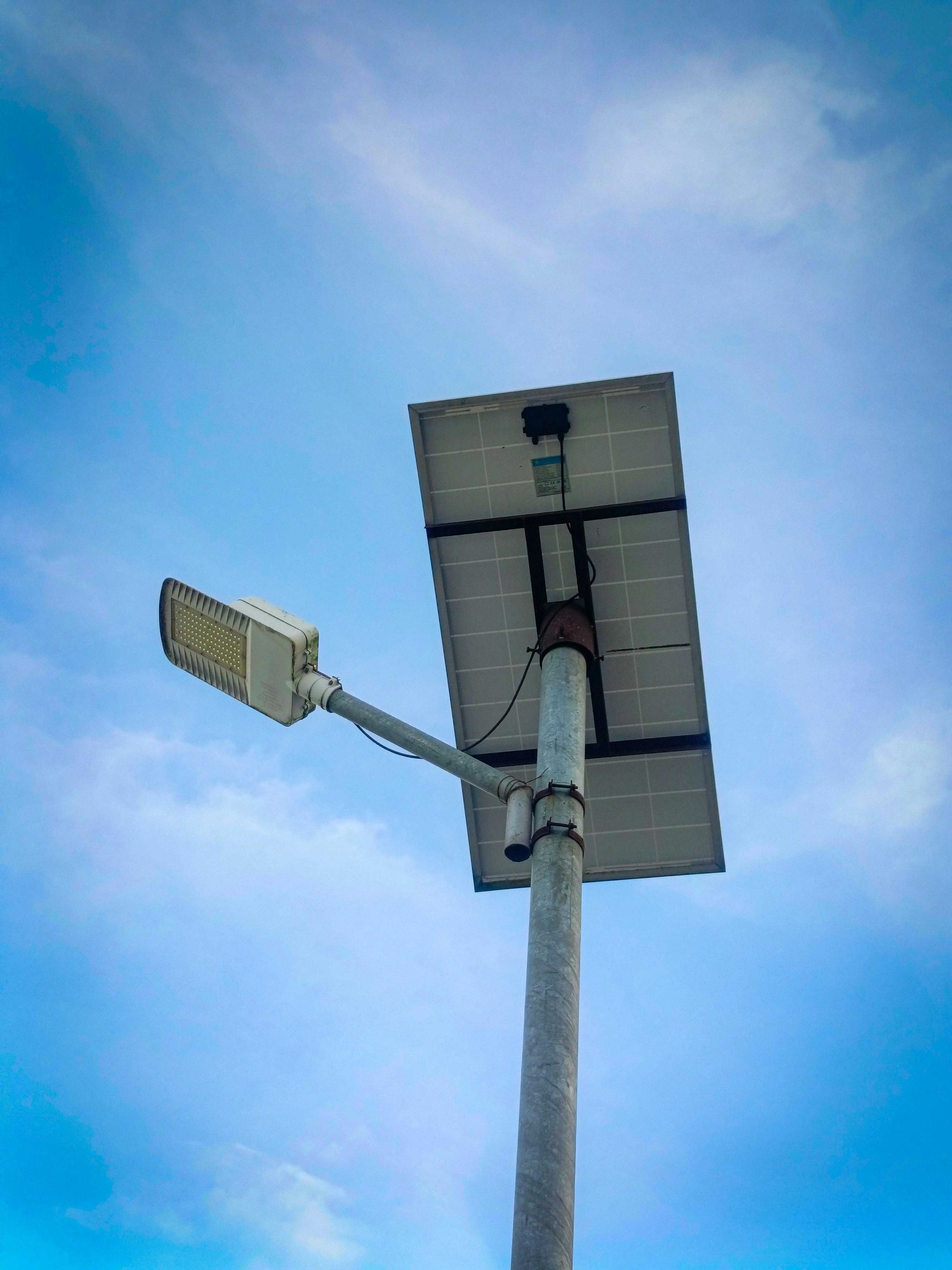 Solar street light vertical pole with attached lantern against a clear blue sky.