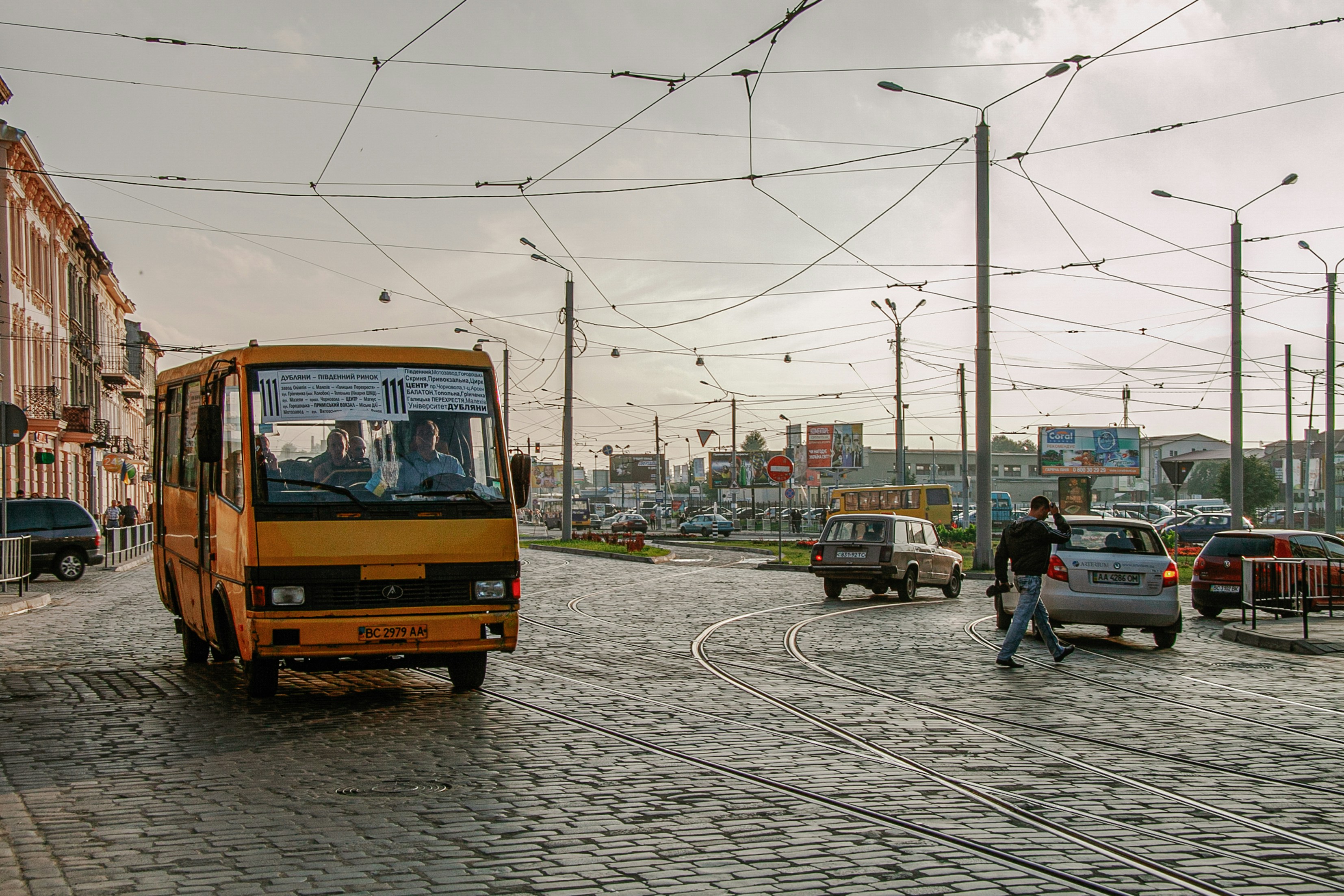 Orange Tram at a Cobblestone Crossing Under a Tangle of Wires