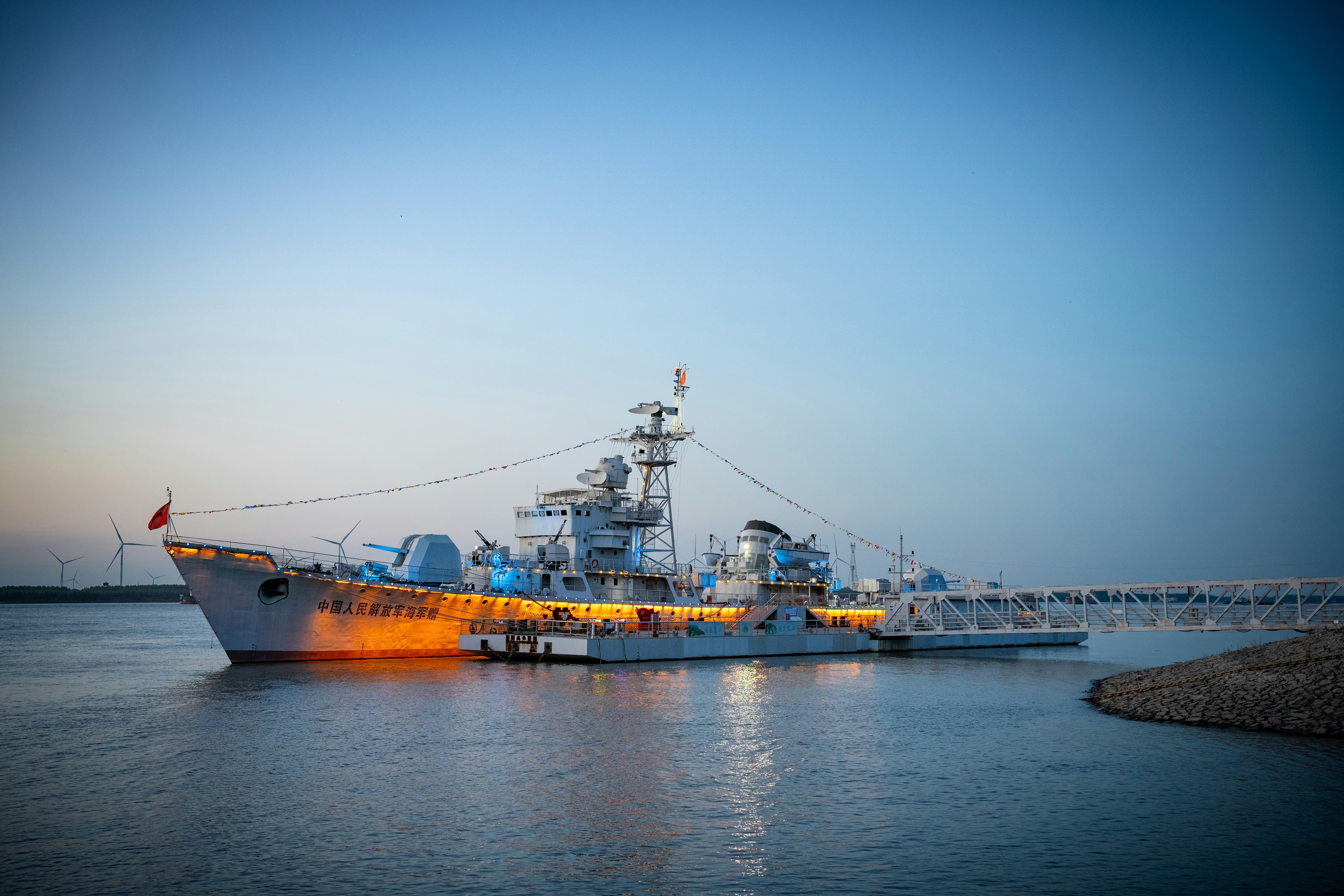 Golden Hour Warship: A Vessel Illuminated Along a Quiet Waterfront