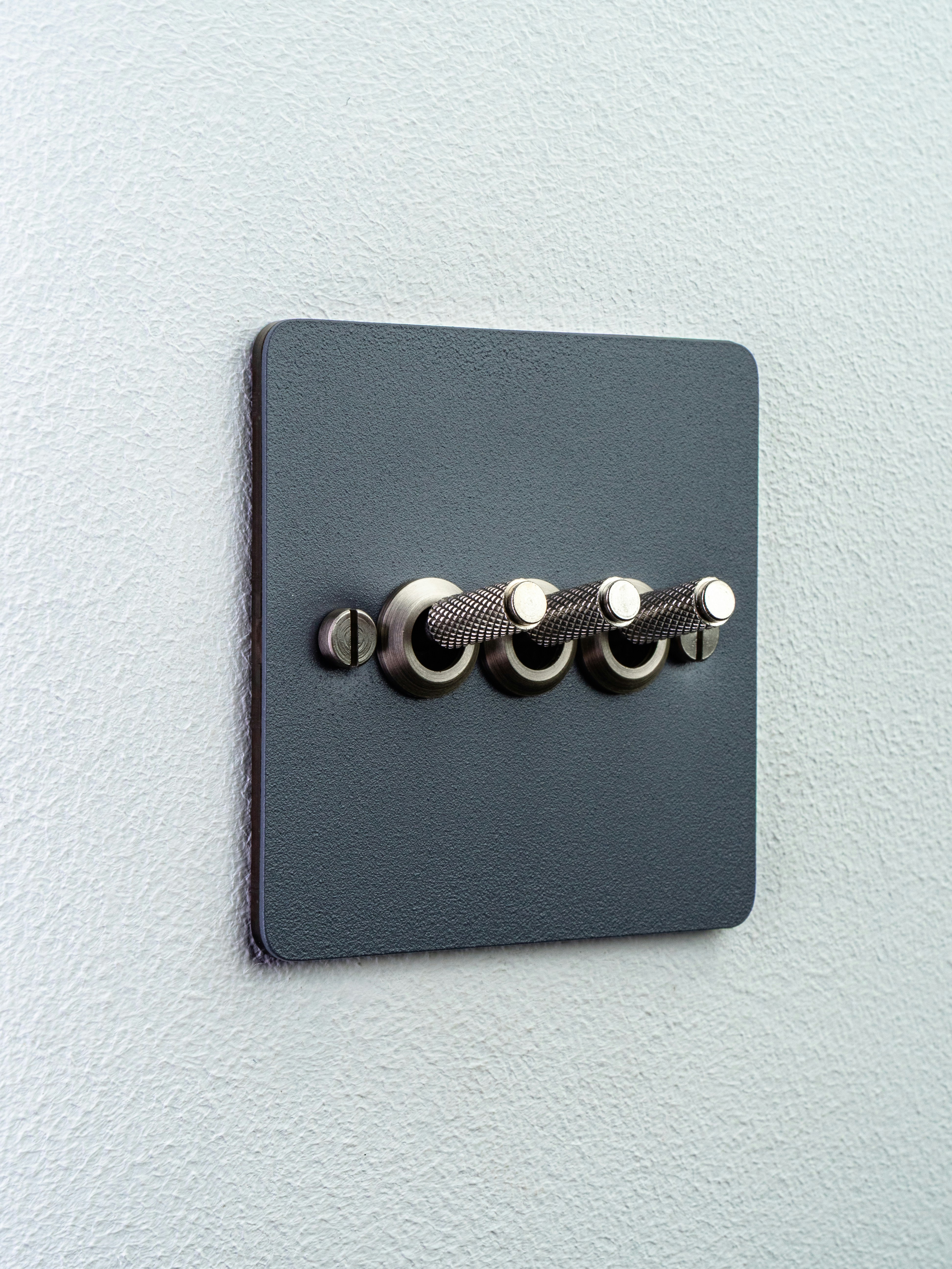 Industrial Minimalism: Four Knurled Levers on a Dark Plate