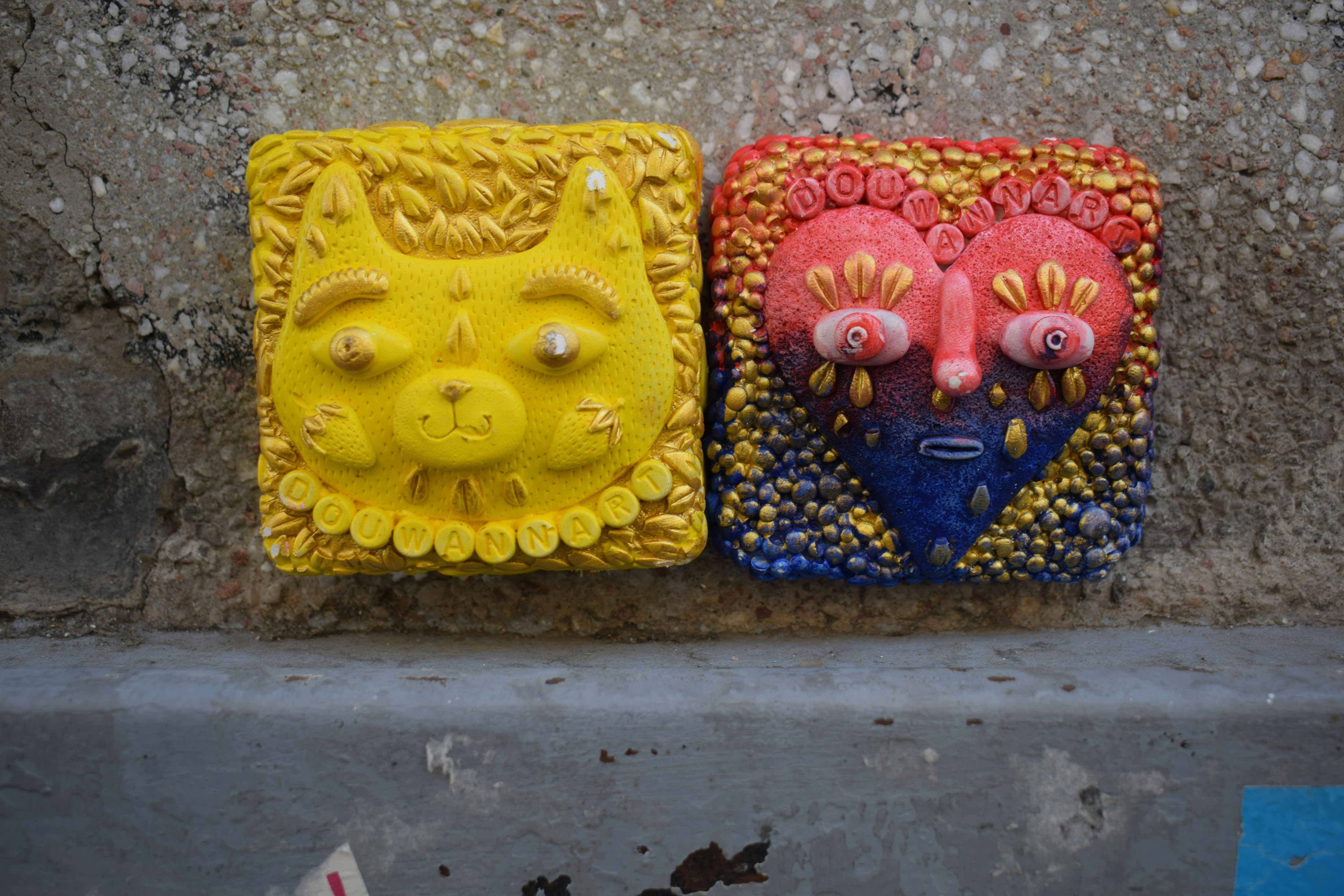Two Playful Ceramic Faces: Yellow Sun and Red-Hued Buddy