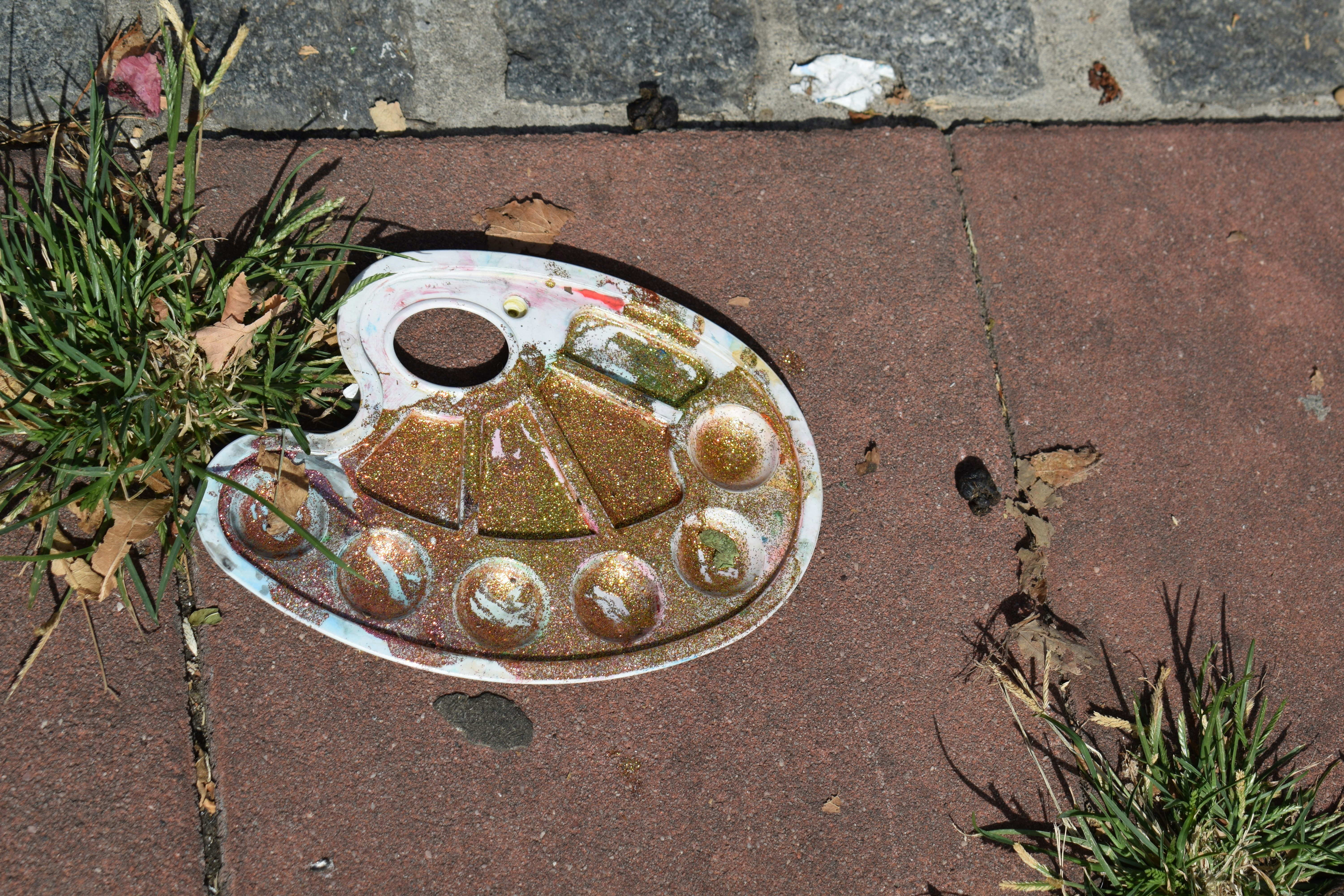 Rusty Utility Disc: A Damaged Manhole Cover Resting on Brick and Grass