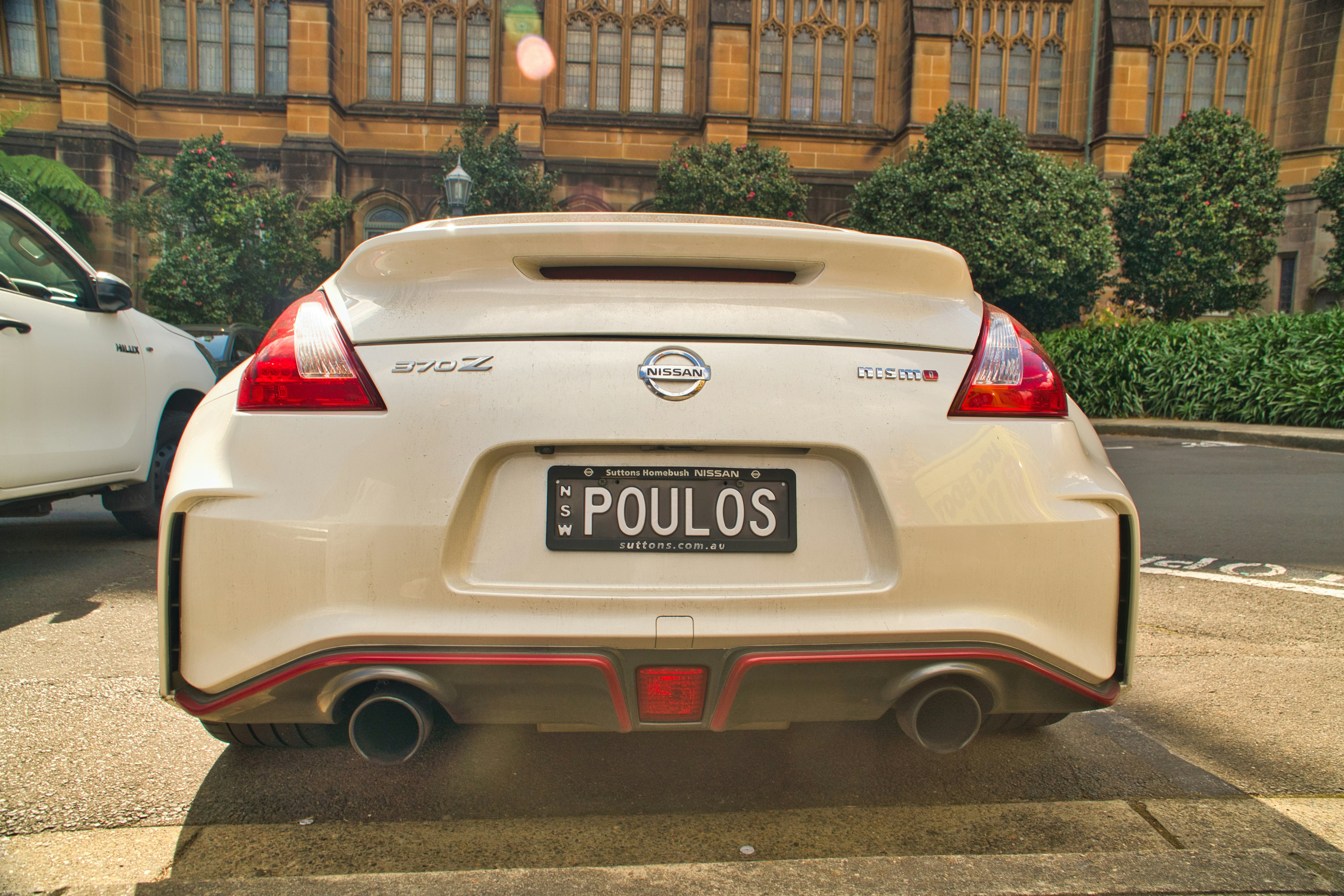 Rear view of a cream Nissan sports coupe with Personalized POULOS plate at dusk
