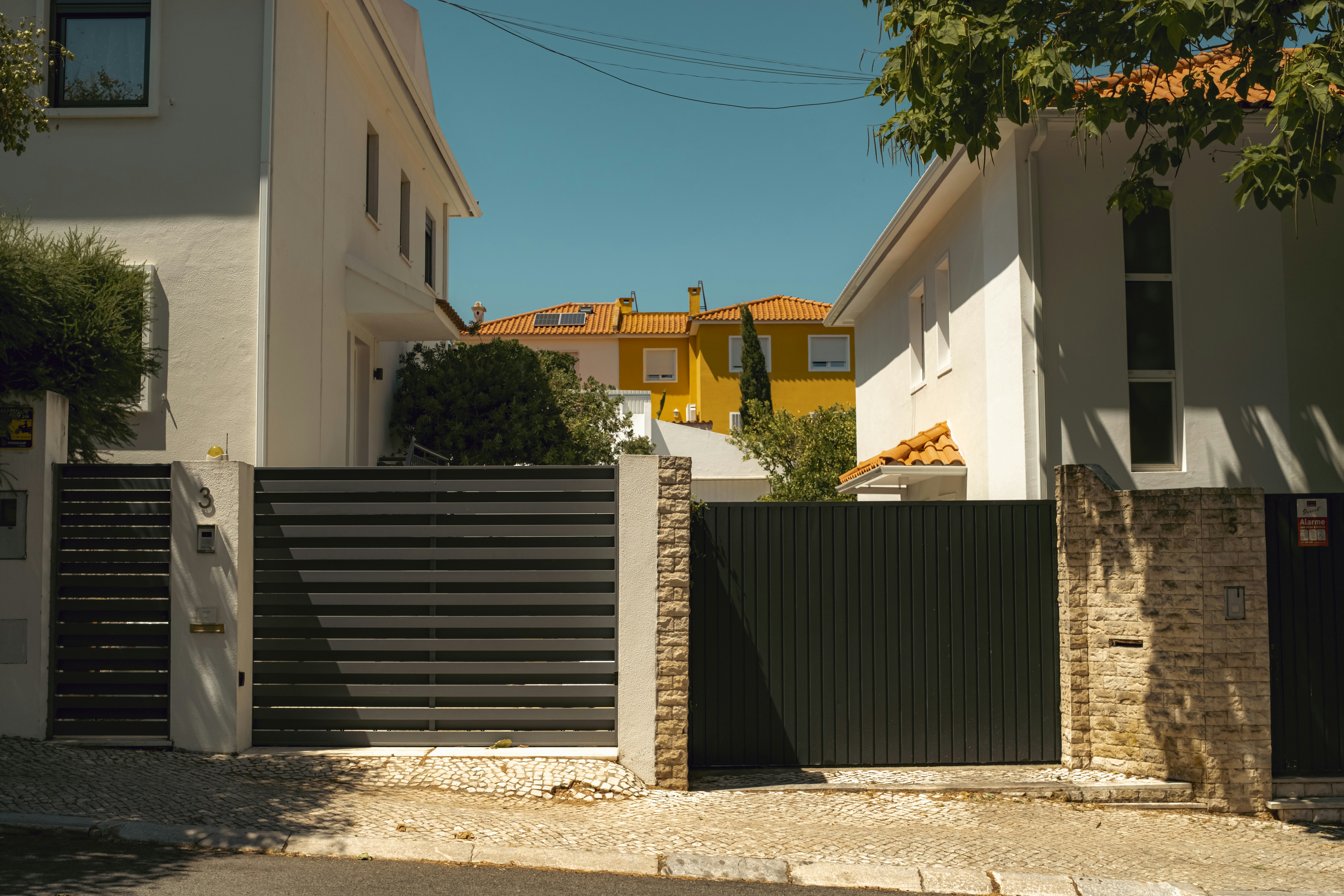 Gated Quiet: A Sunlit Mediterranean Street Framed by Modern Exteriors
