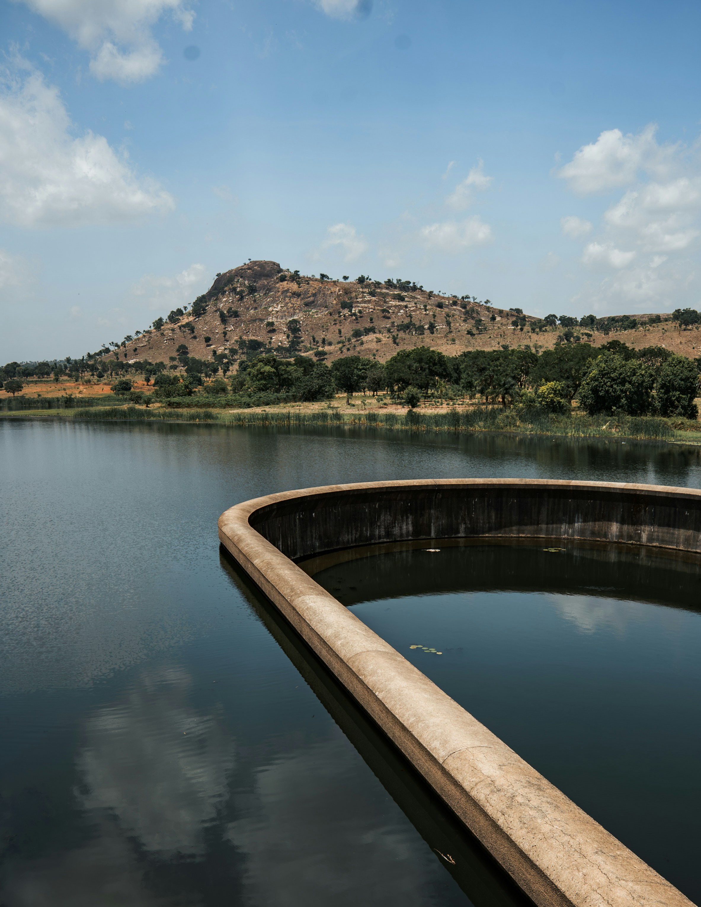 Curved shoreline of a reservoir framing a distant hillside