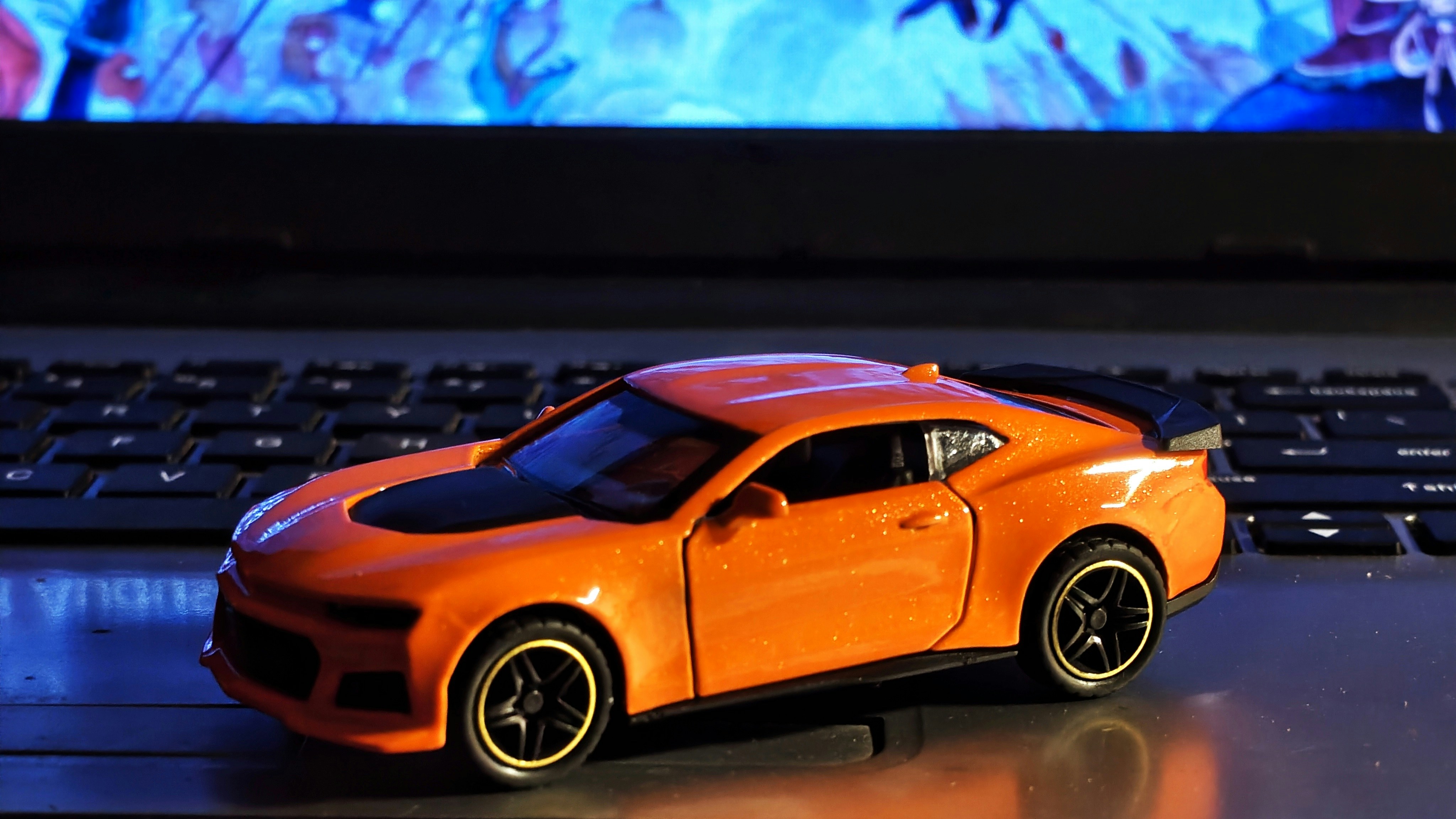 Mini Orange Coupe Rests on a Laptop Keyboard Stage