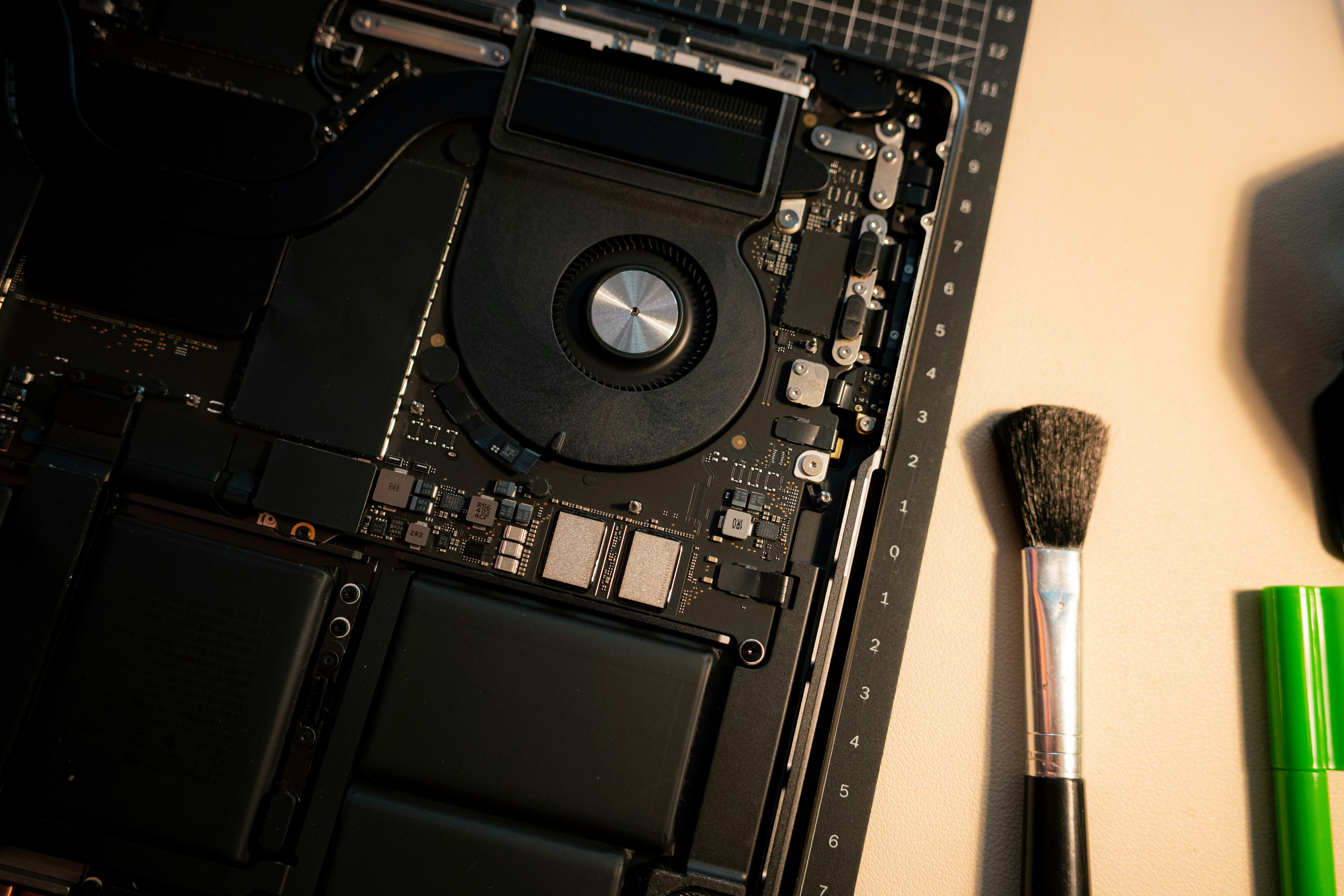 Close-up of a disassembled camera motherboard with a brush and tools at the edge