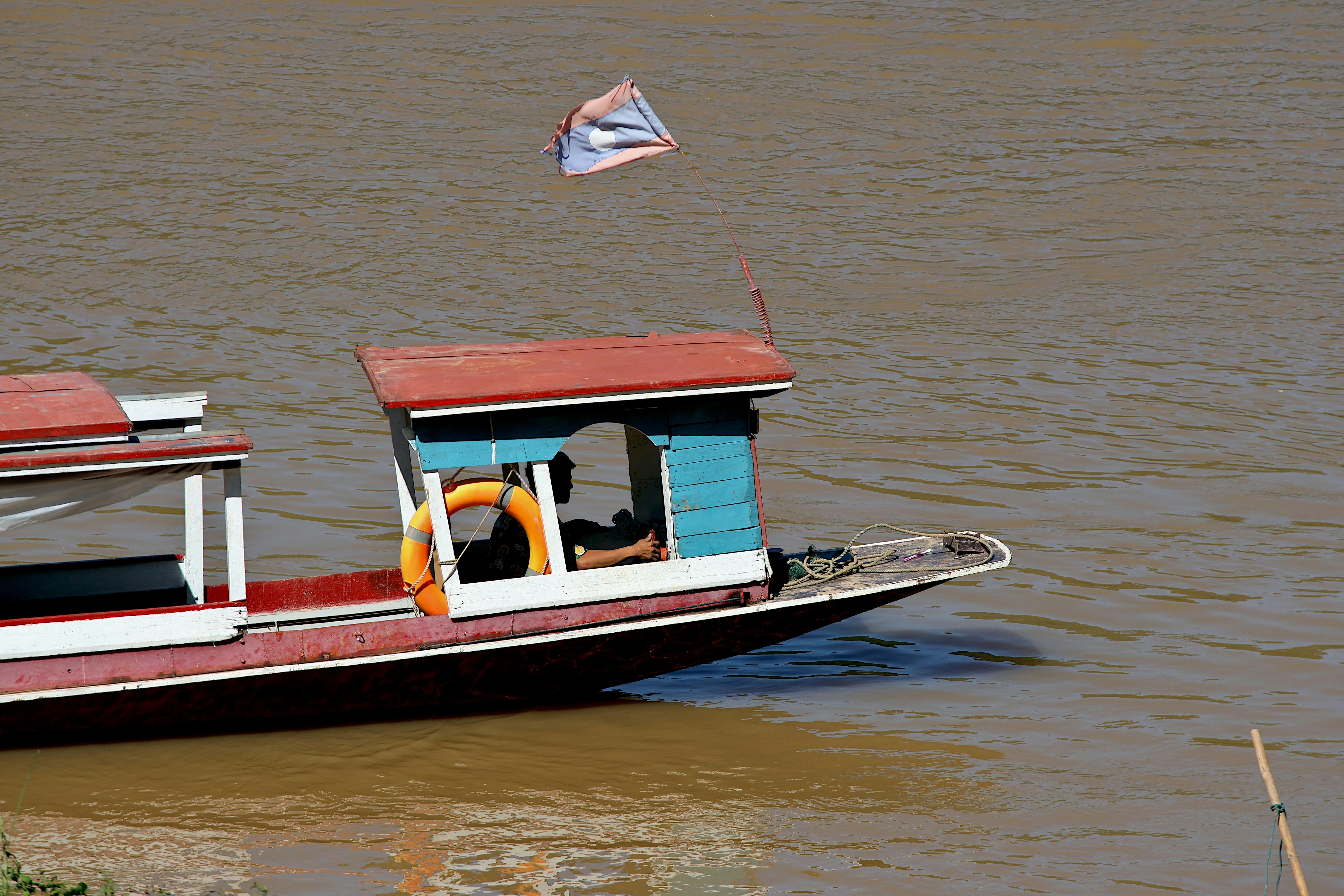 Colorful boathouse on a calm river with a small kite drifting above