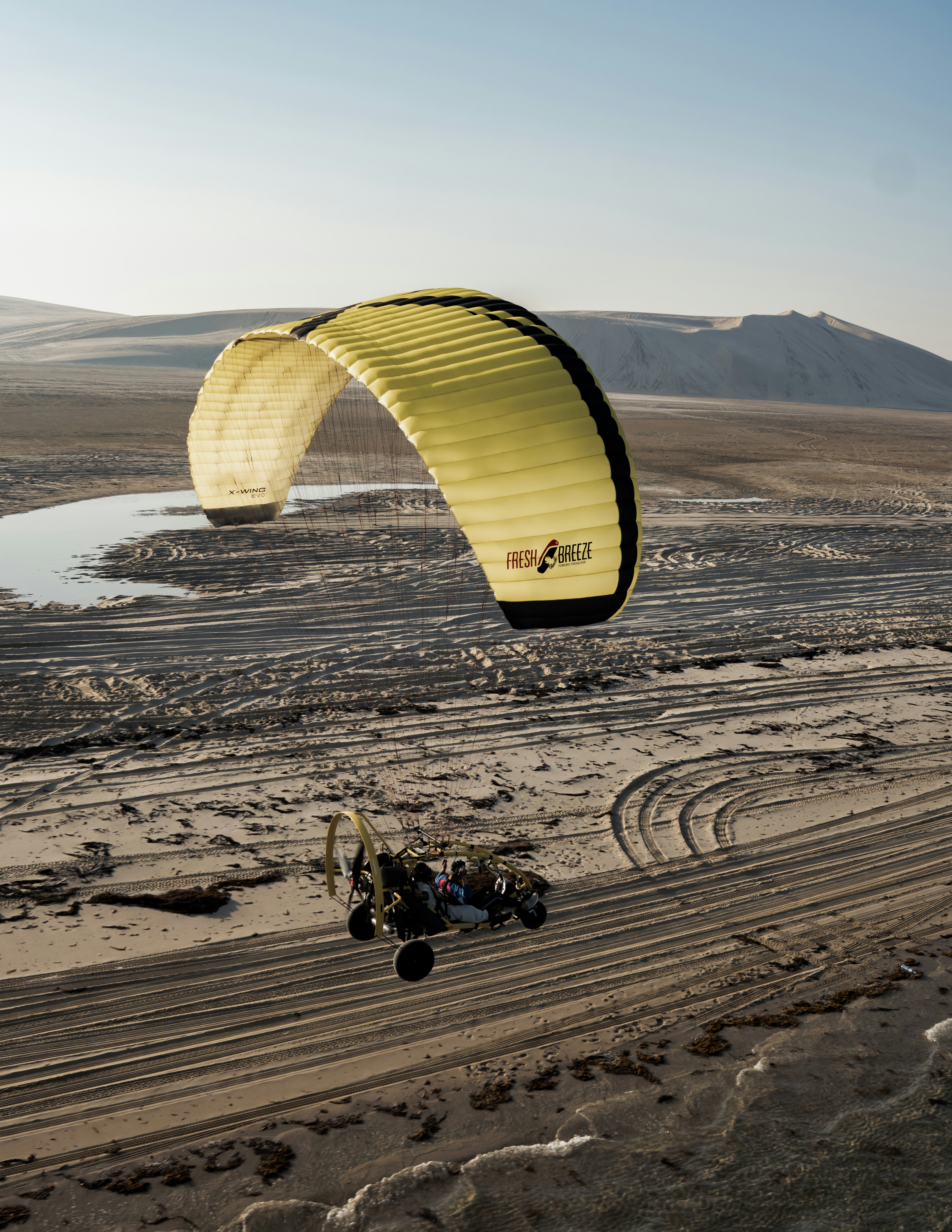 Yellow Paraglider over Desert Tracks