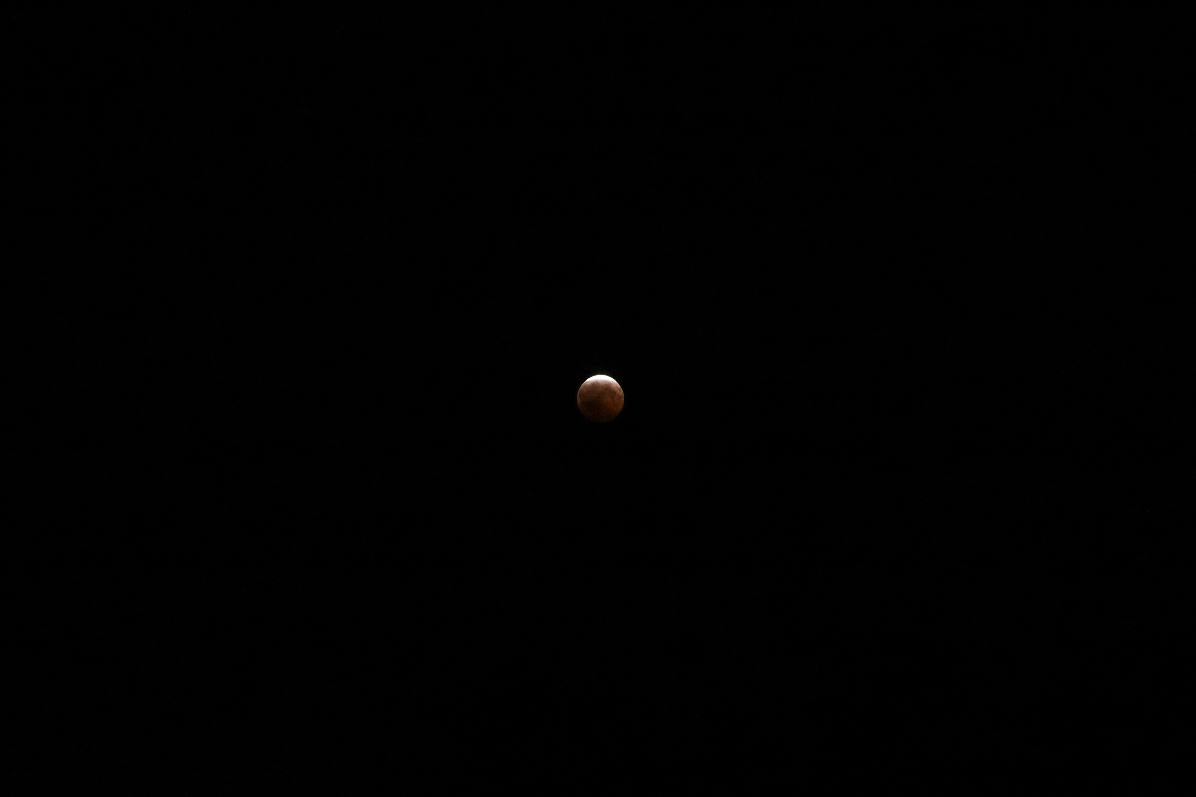 Red-Late Lunar Glow: A Tiny Copper Moon in a Void of Night