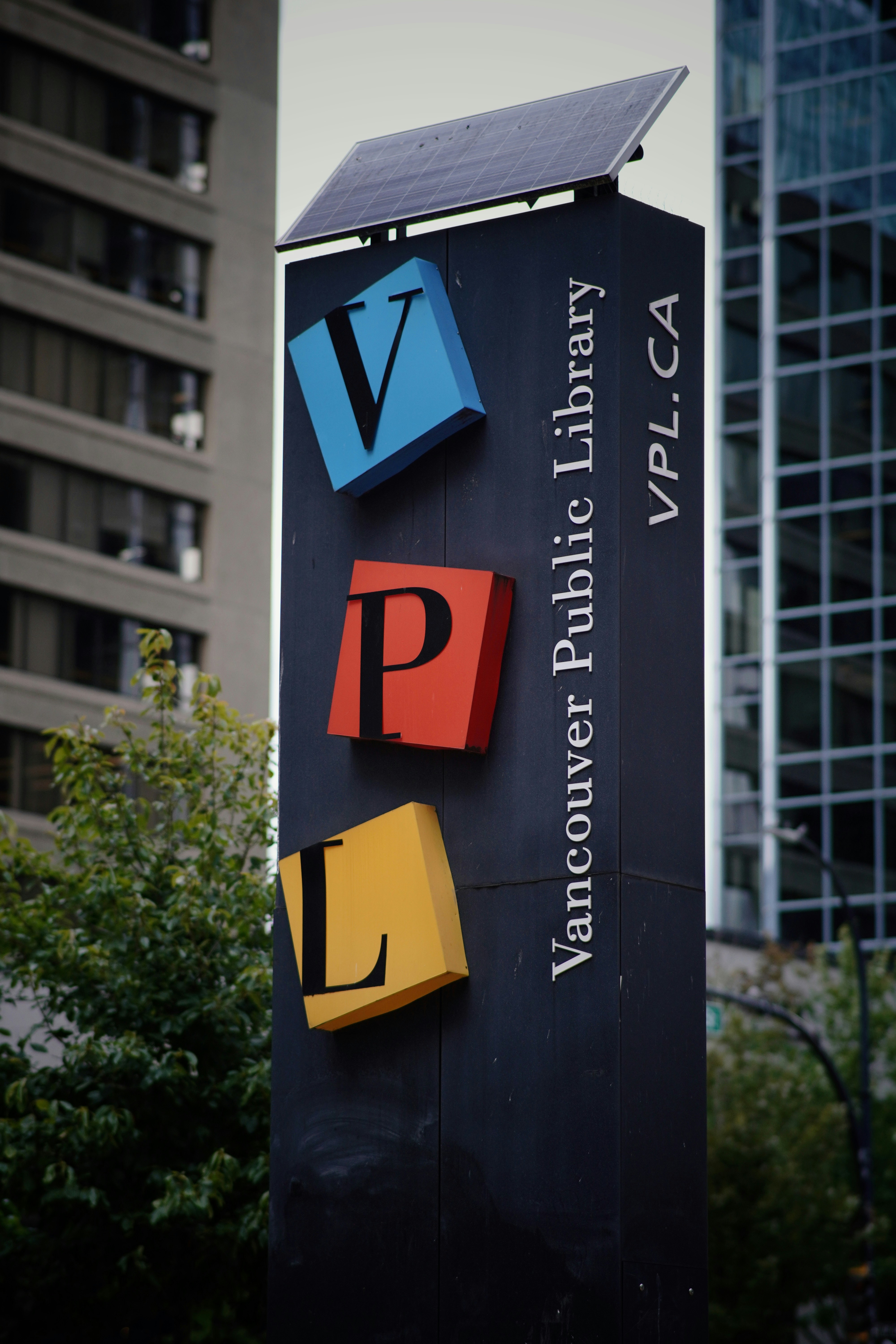 Vertical Beacon: The Vancouver Public Library Sign Rising Above Urban Green