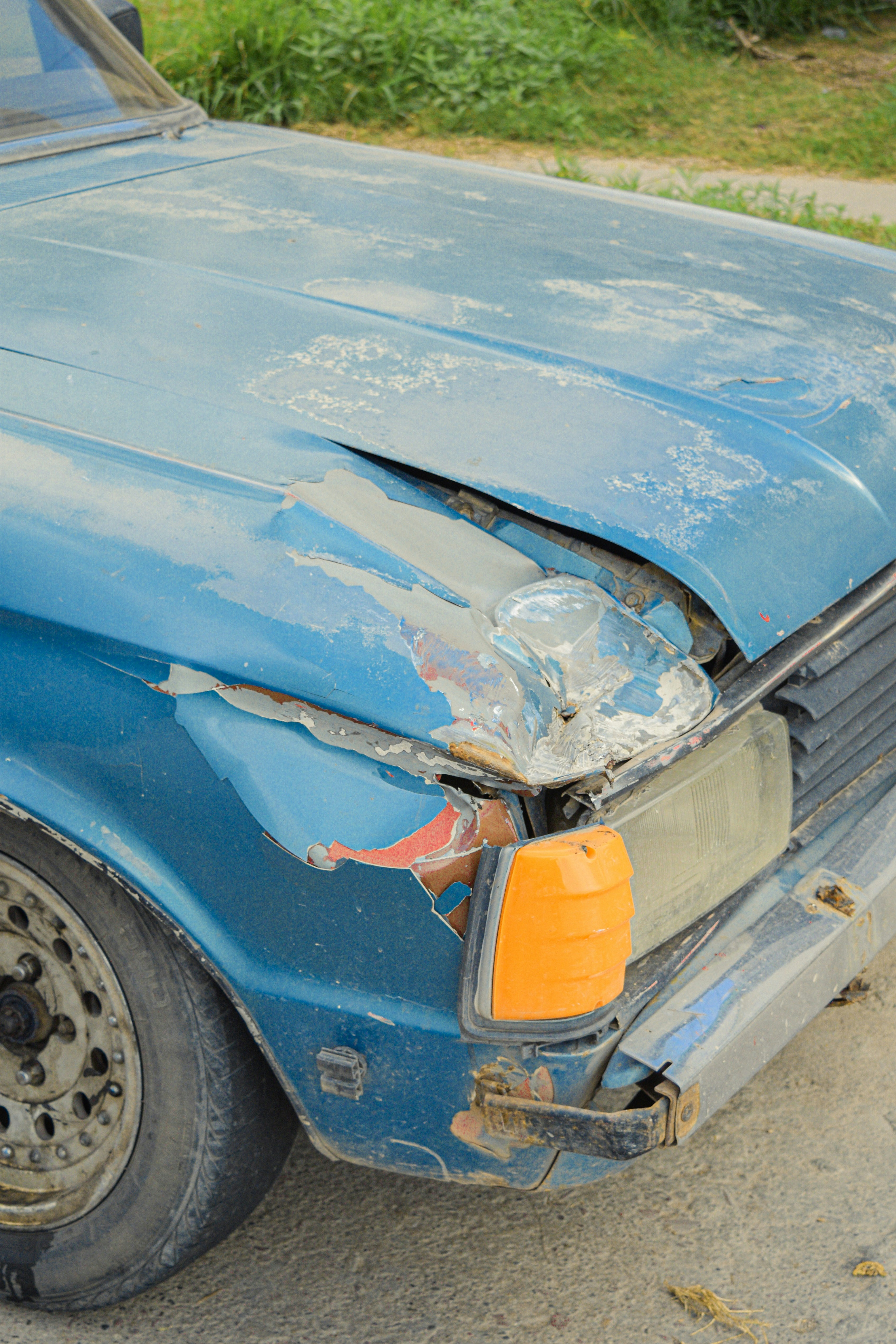 Dented Blue Relic: sunlight catching the battered hood of a vintage truck