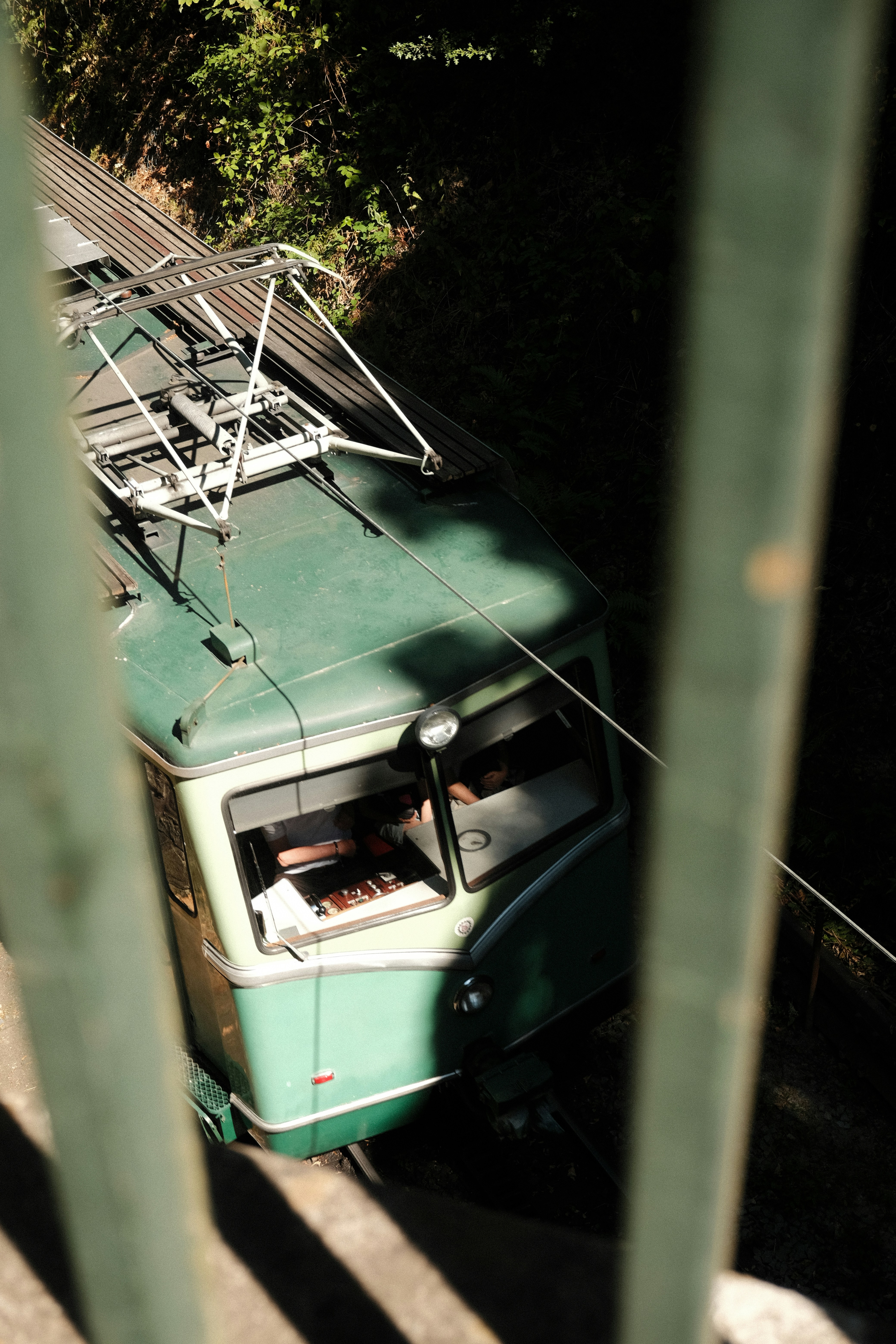 Up Close on Rails: A Green Tram Trundles Through a Narrow Scene