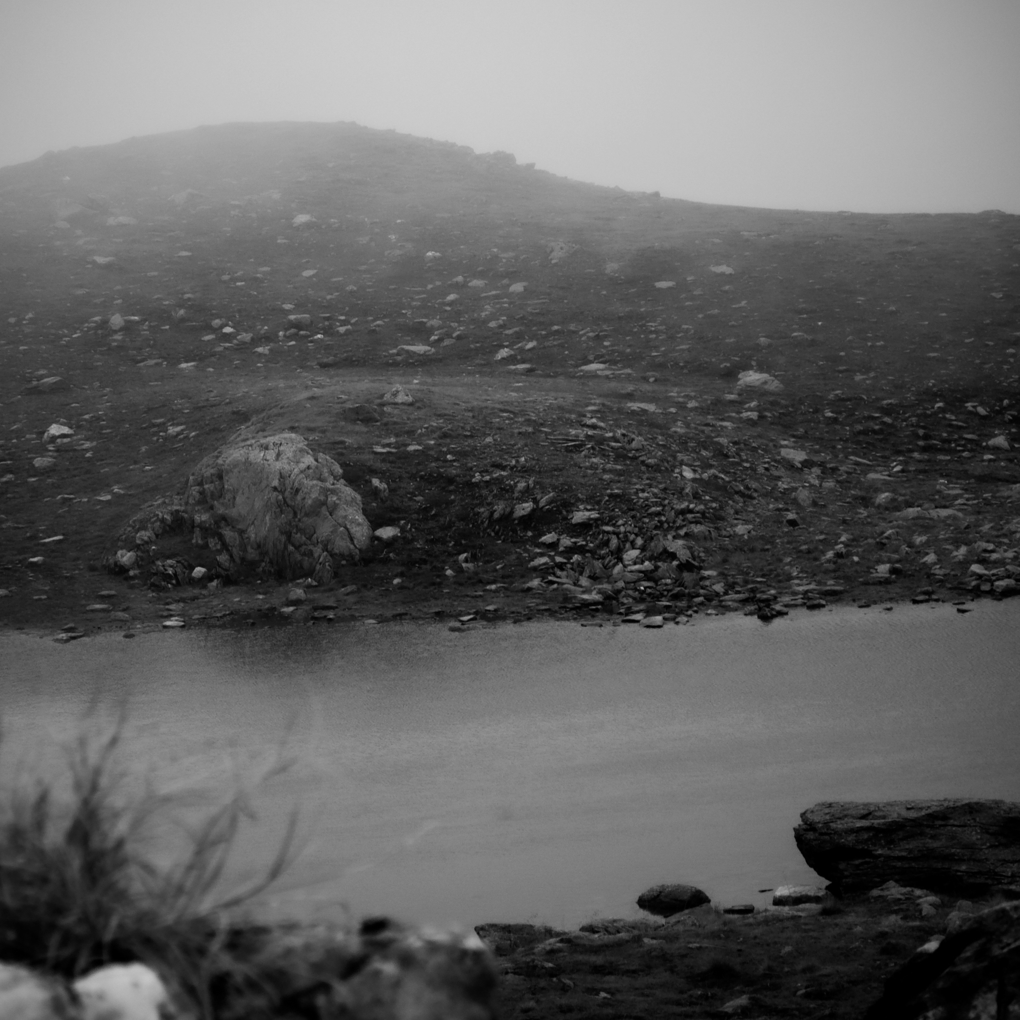 A high-alpine lake surrounded by low clouds.