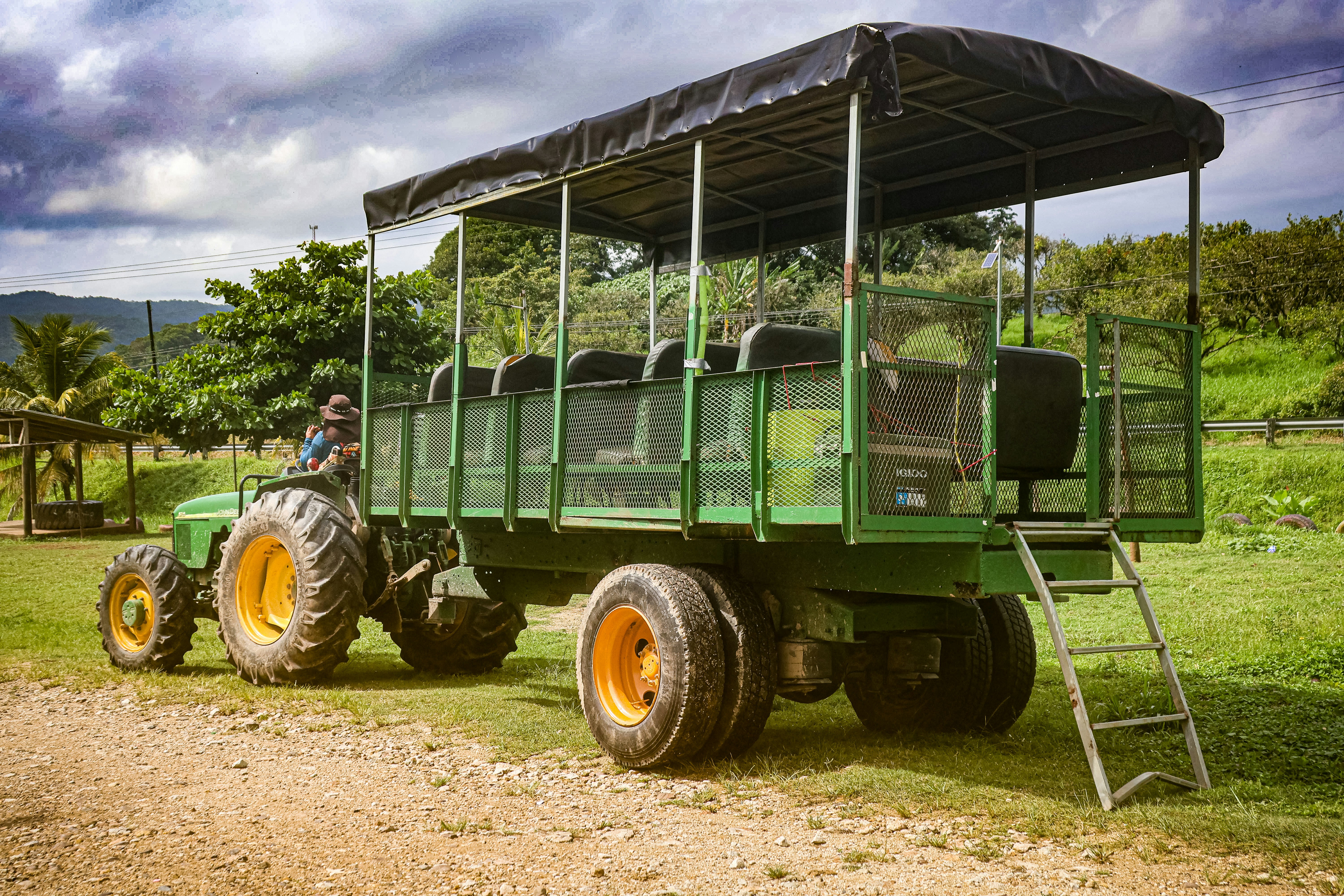 Green Hauler in Sunlit Field: A Tractor Tour on Rough Gravel