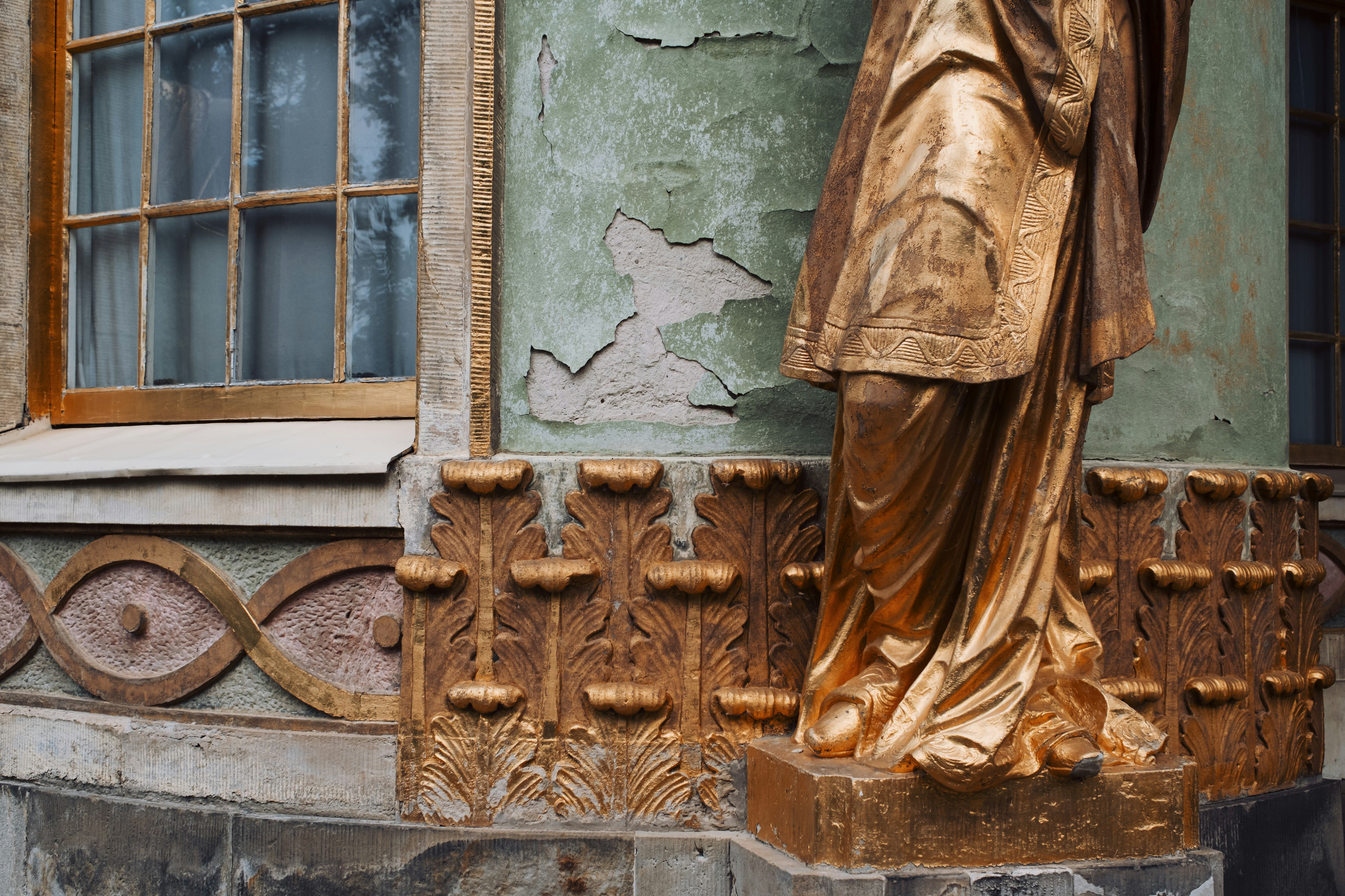 Weathered pedestal and gilded statue: a quiet street-side sculpture reveal