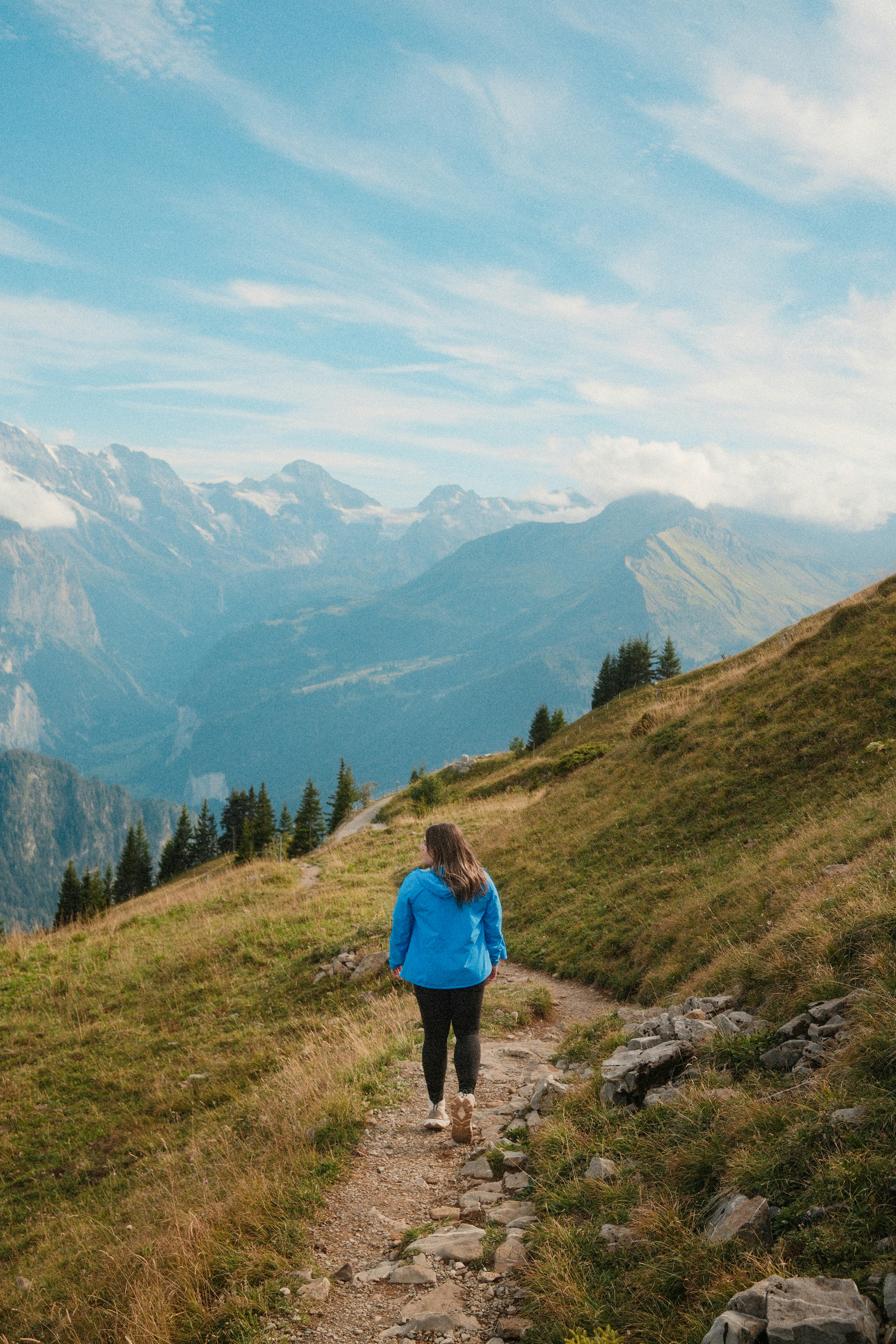 Hiker in a Blue Jacket Descends a Mountain Corridor