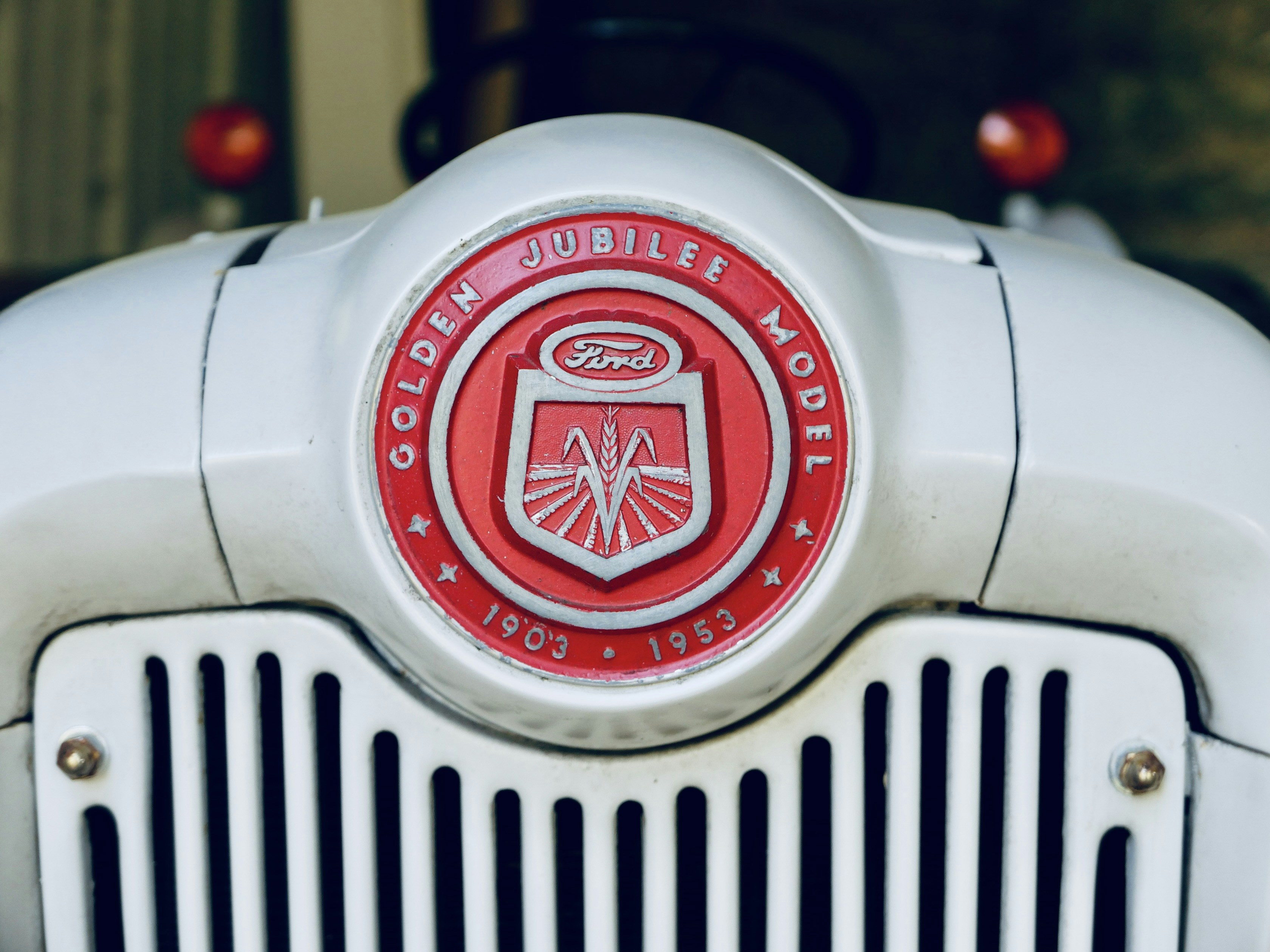 Vintage Ford Crest: A Close-Up of the Emblem Amid White Grilles