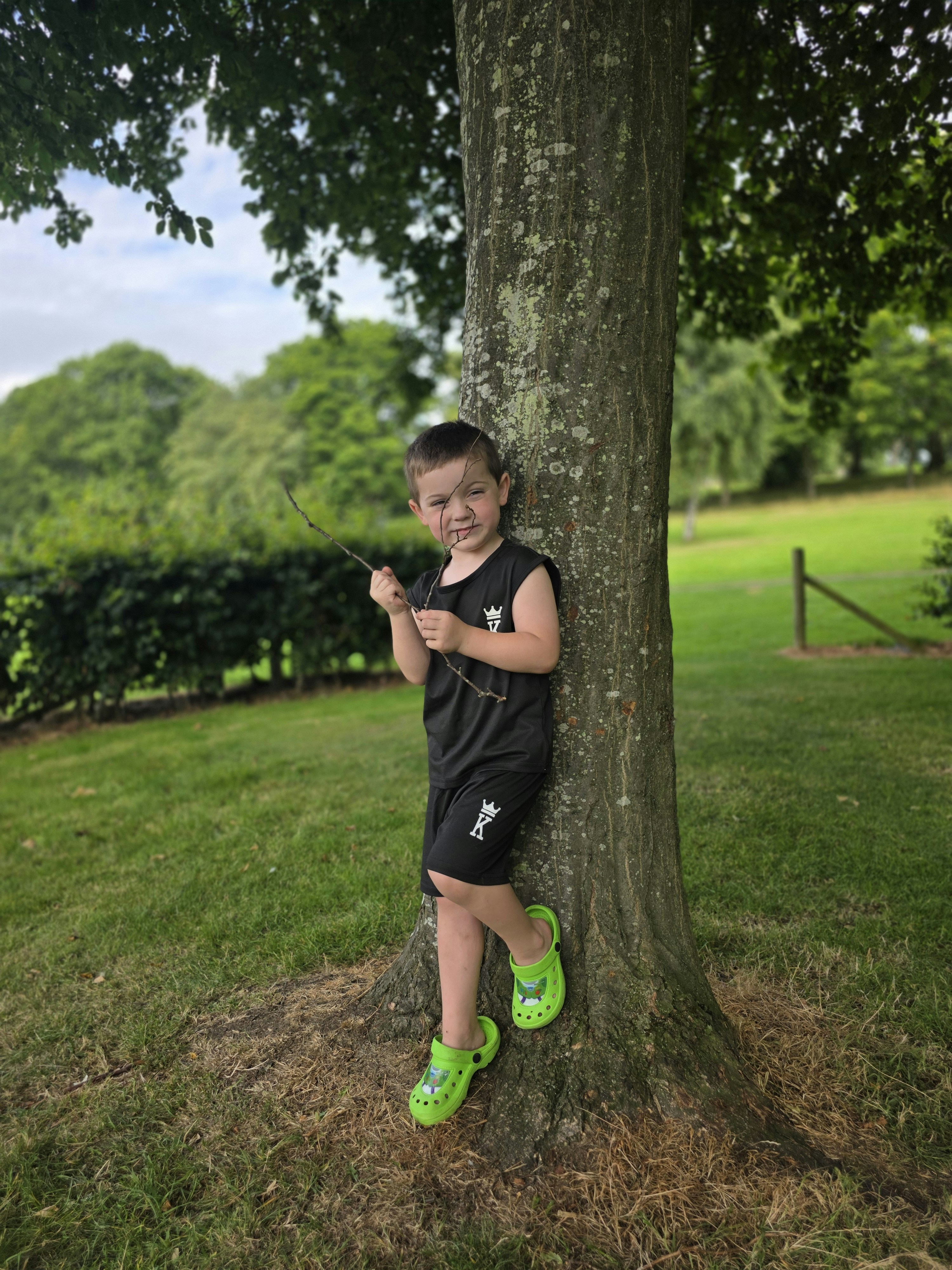 Child Leans Against a Tree in Sunlit Park