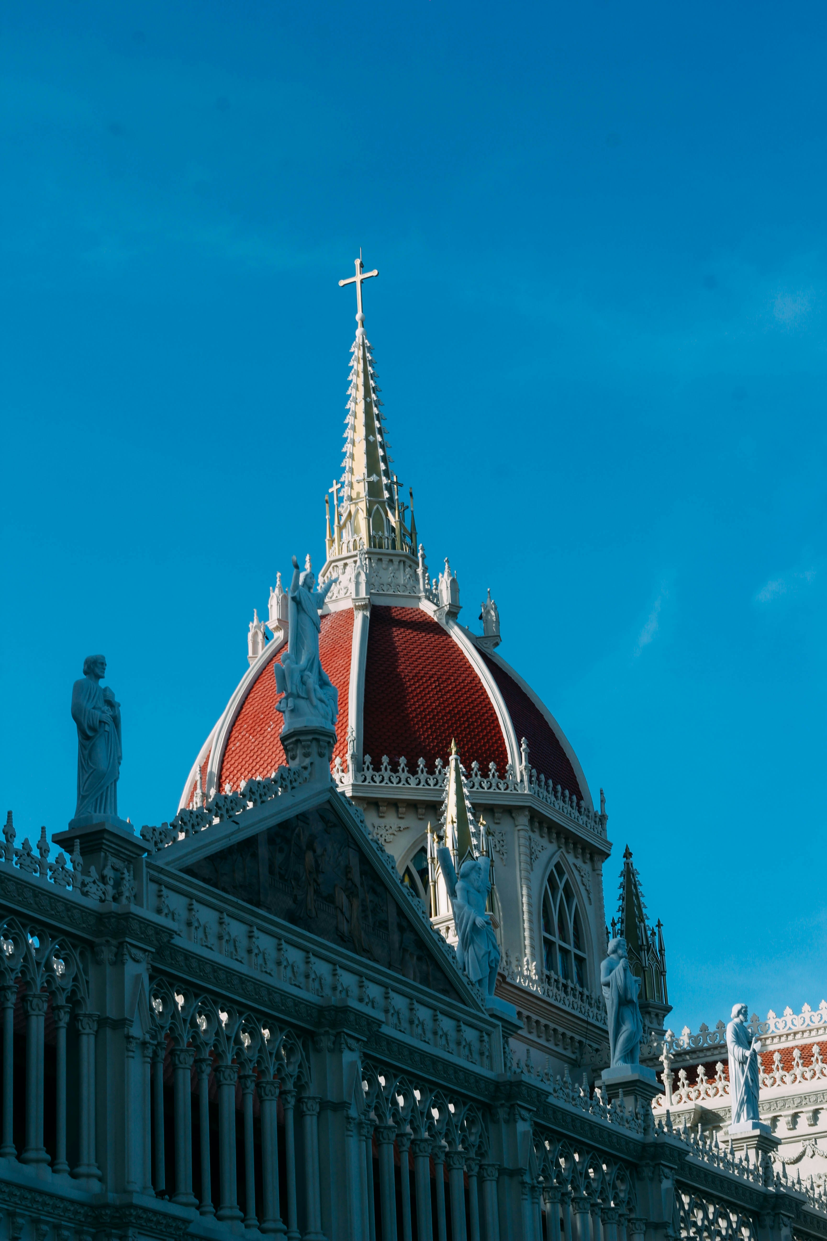 Spire crowned by Cross: Sunlit Cathedral Dome Against Clear Sky
