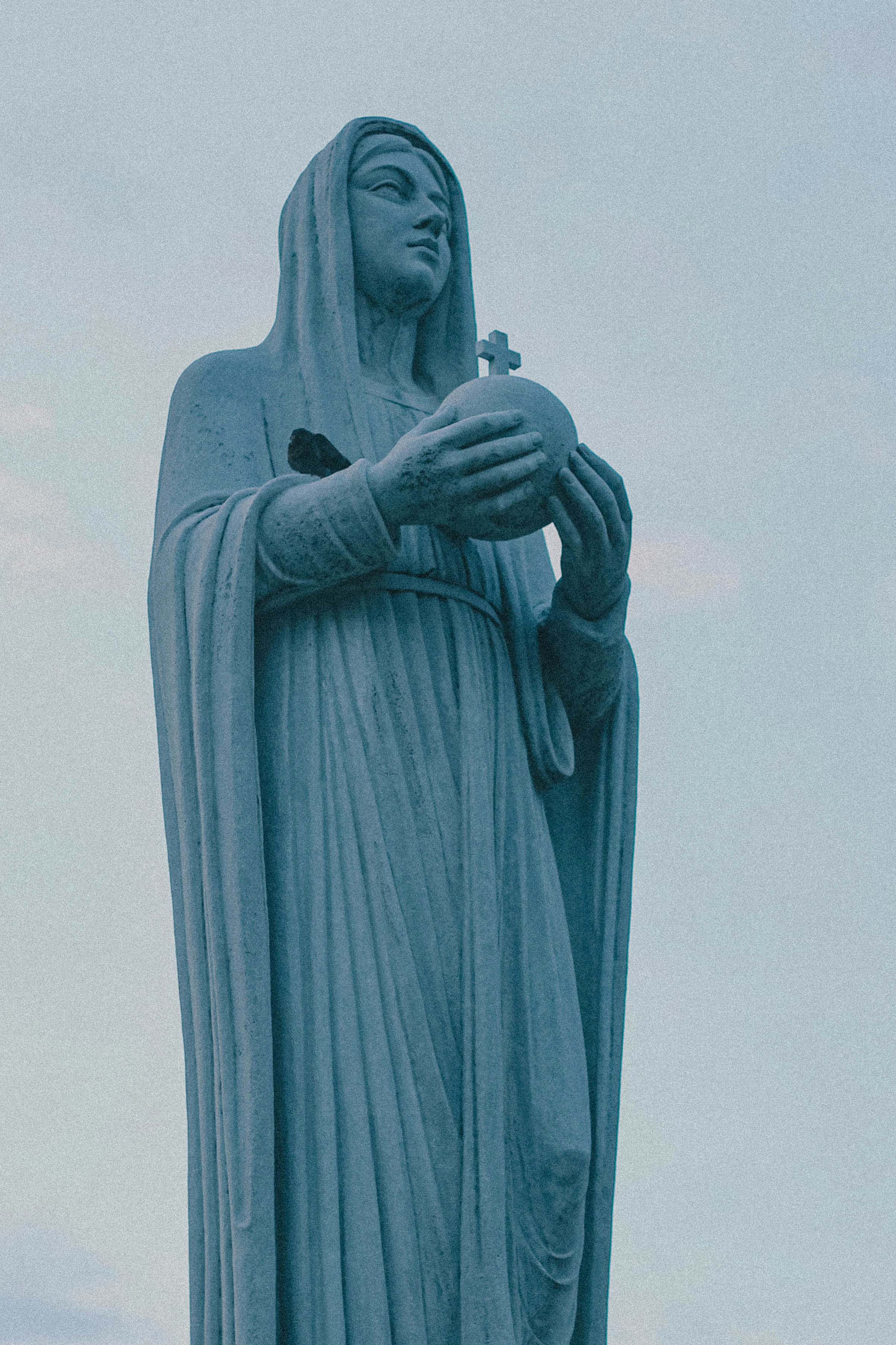 Holding the World: A solemn statue under a pale sky