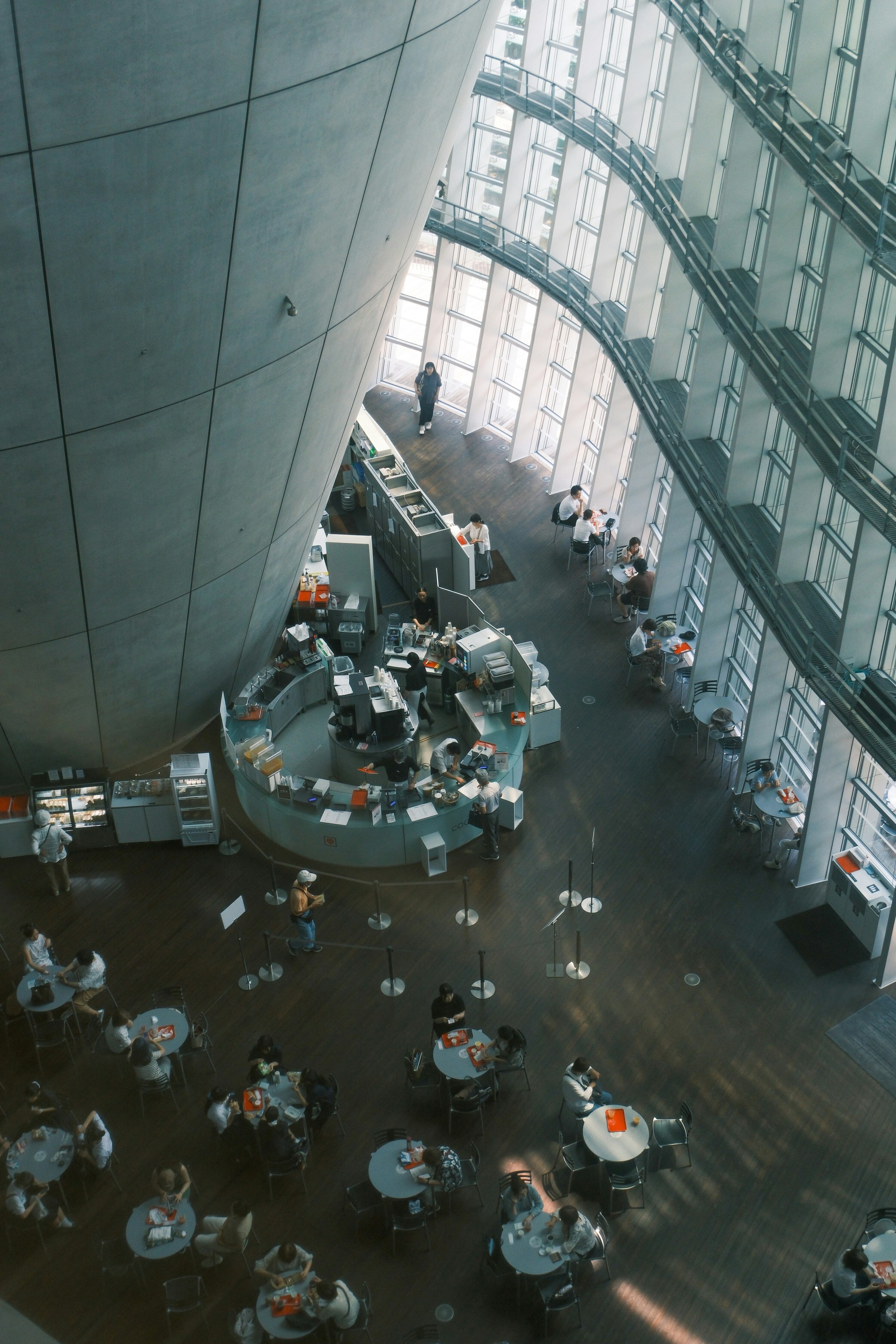 Atrium Quietude: People Gather Around a Curved Information Desk Beneath Glass and Steel