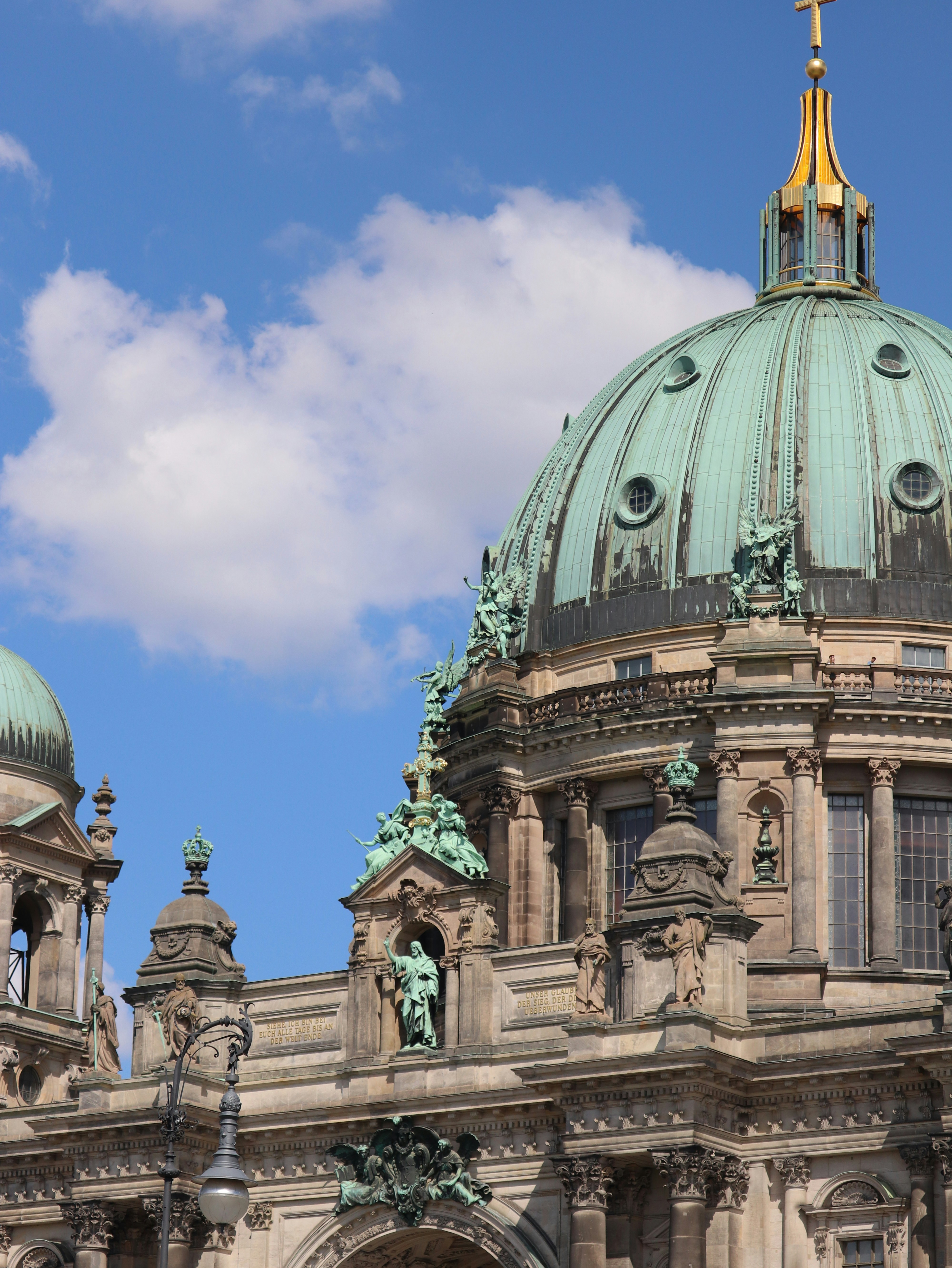 Ornate European cathedral dome and façade rise against a bright blue sky, highlighting sculptural details and patinated copper. This architectural scene emphasizes craftsmanship and historic grandeur.