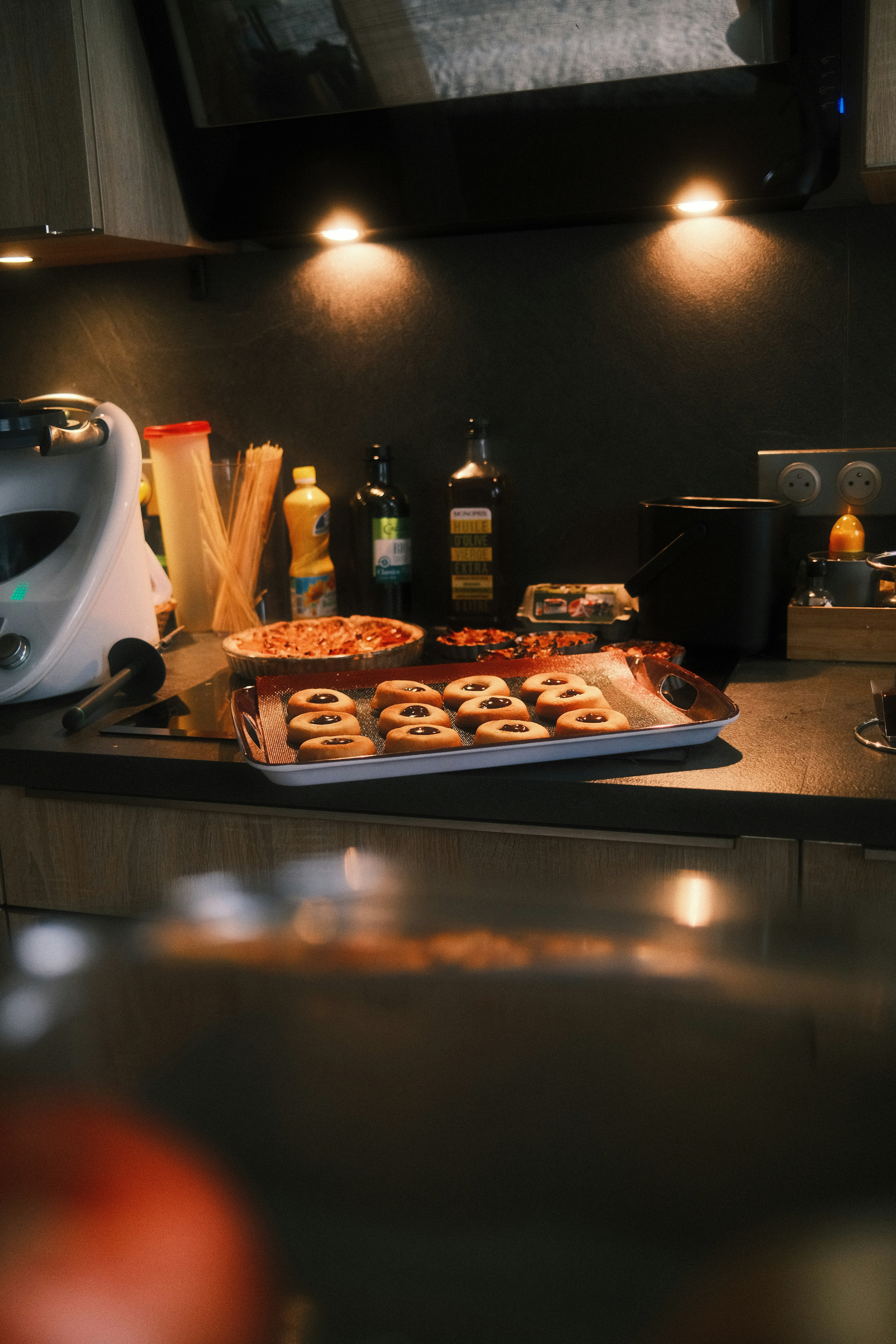 Tray of glazed donuts under kitchen lights