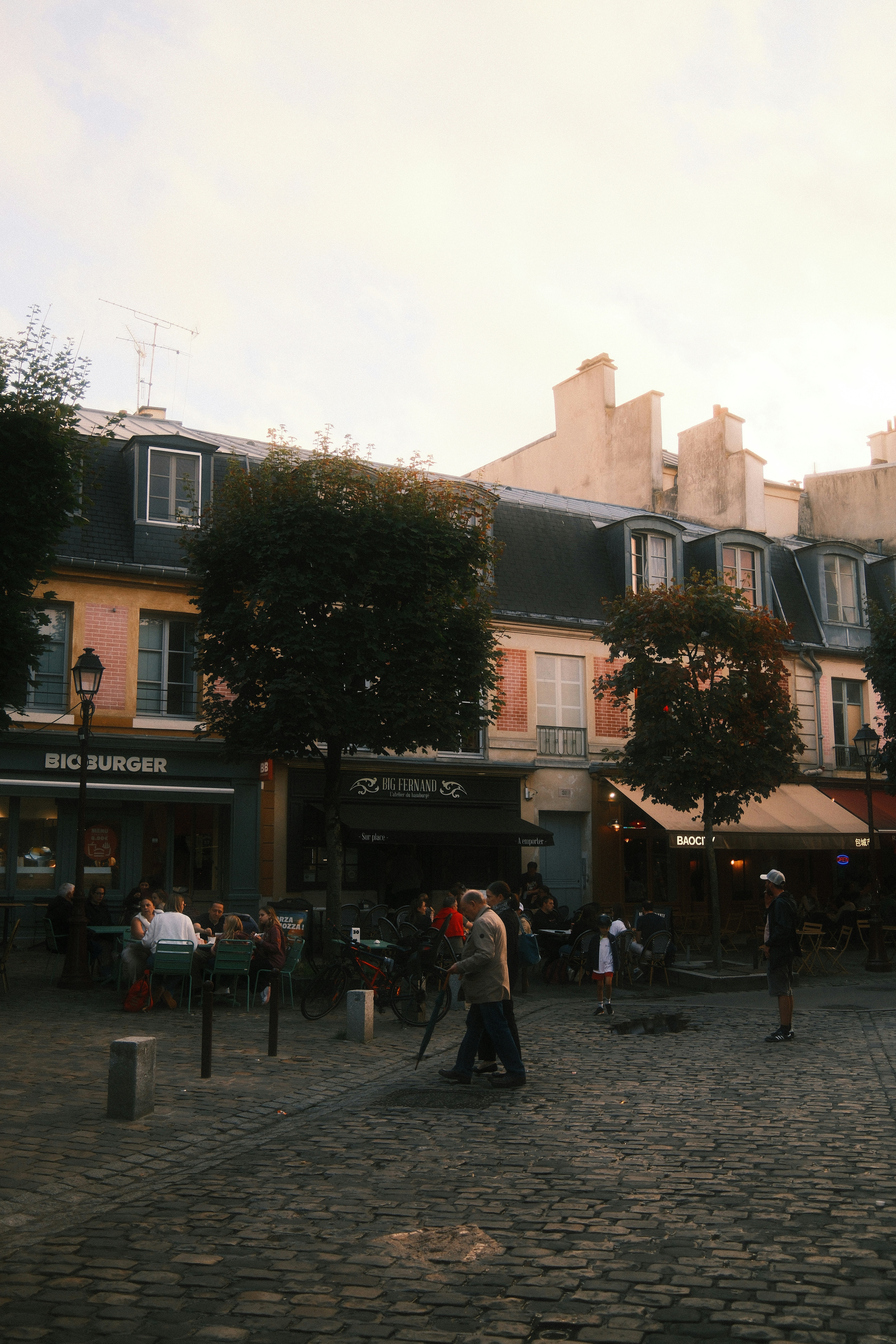 Cobbled Square Serenade: People and Café Under Soft Evening Light