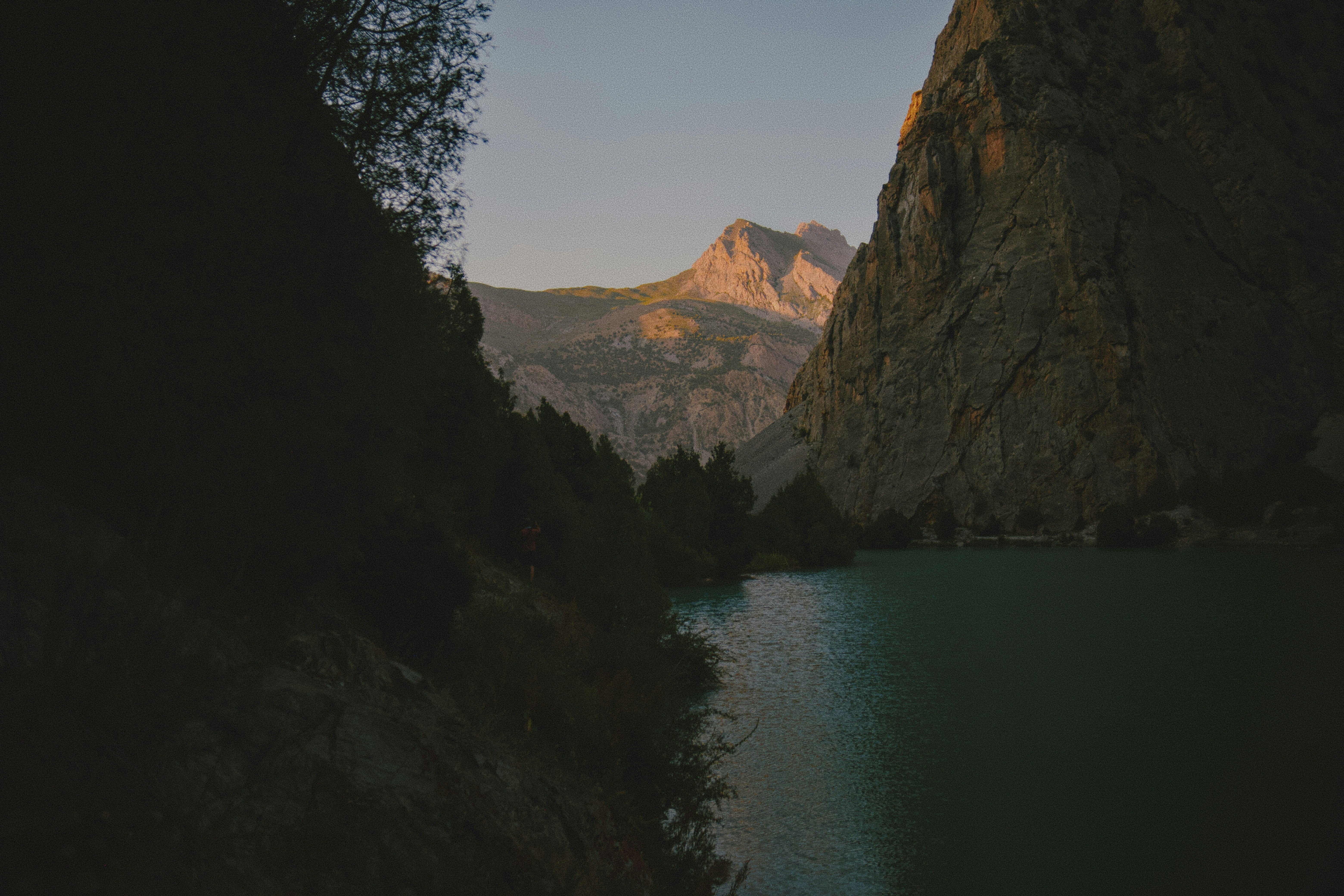 A turquoise lake nestled between steep rocky cliffs under a clear sky