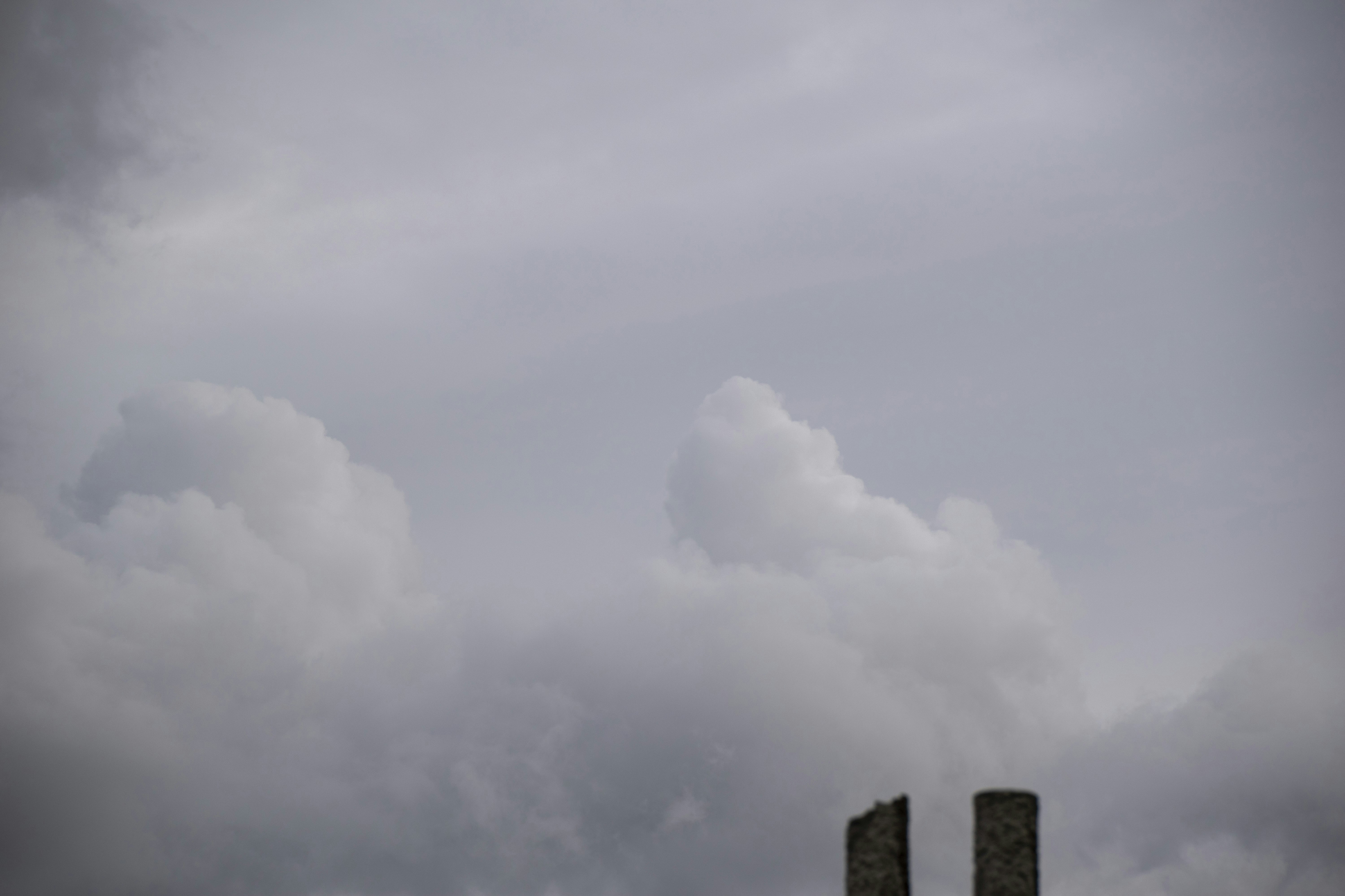 Clouds over a distant chimney silhouette at dusk