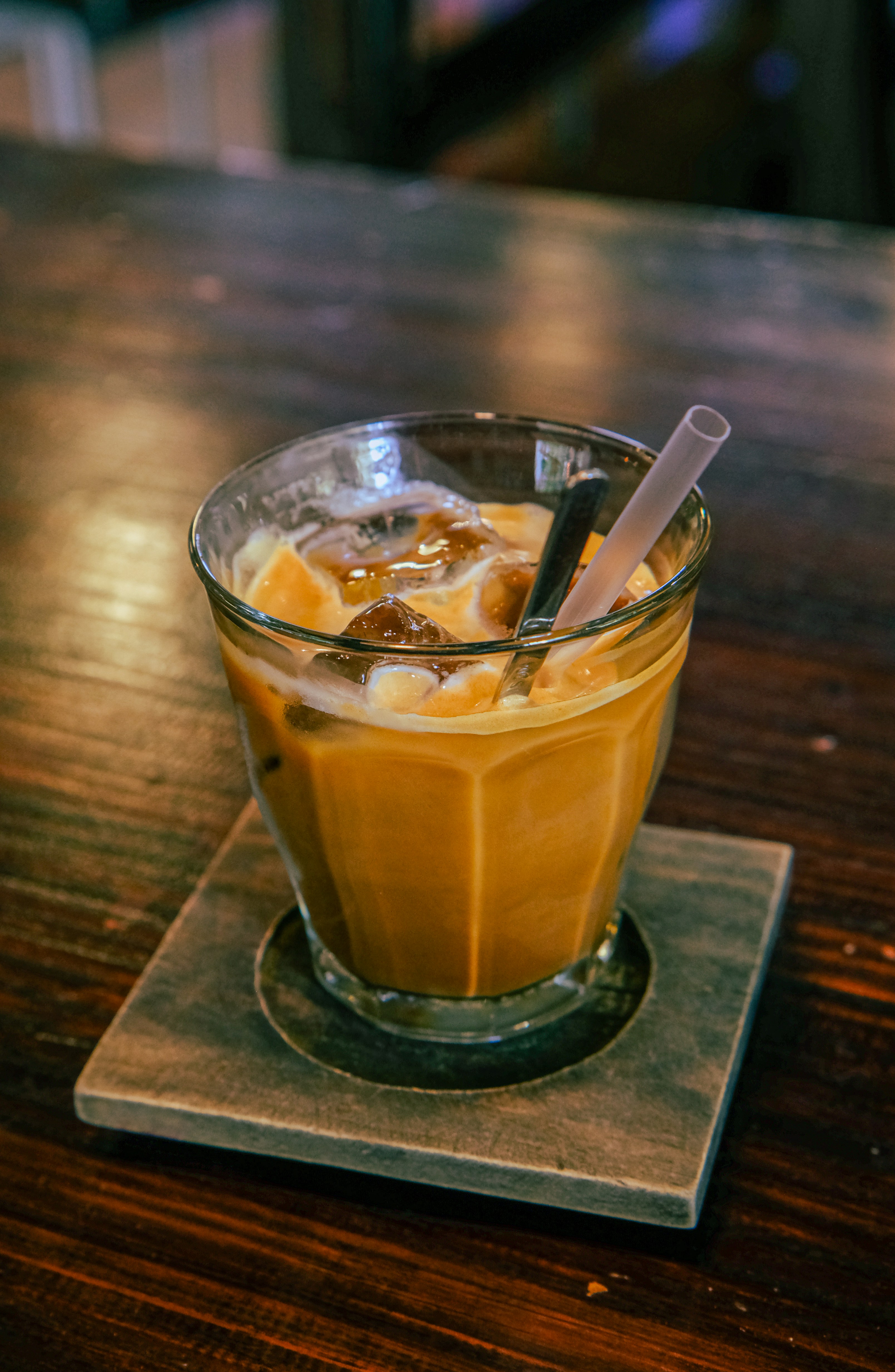 Creamy Espresso Glow: A Glass of Iced Caramel on a Wooden Bar