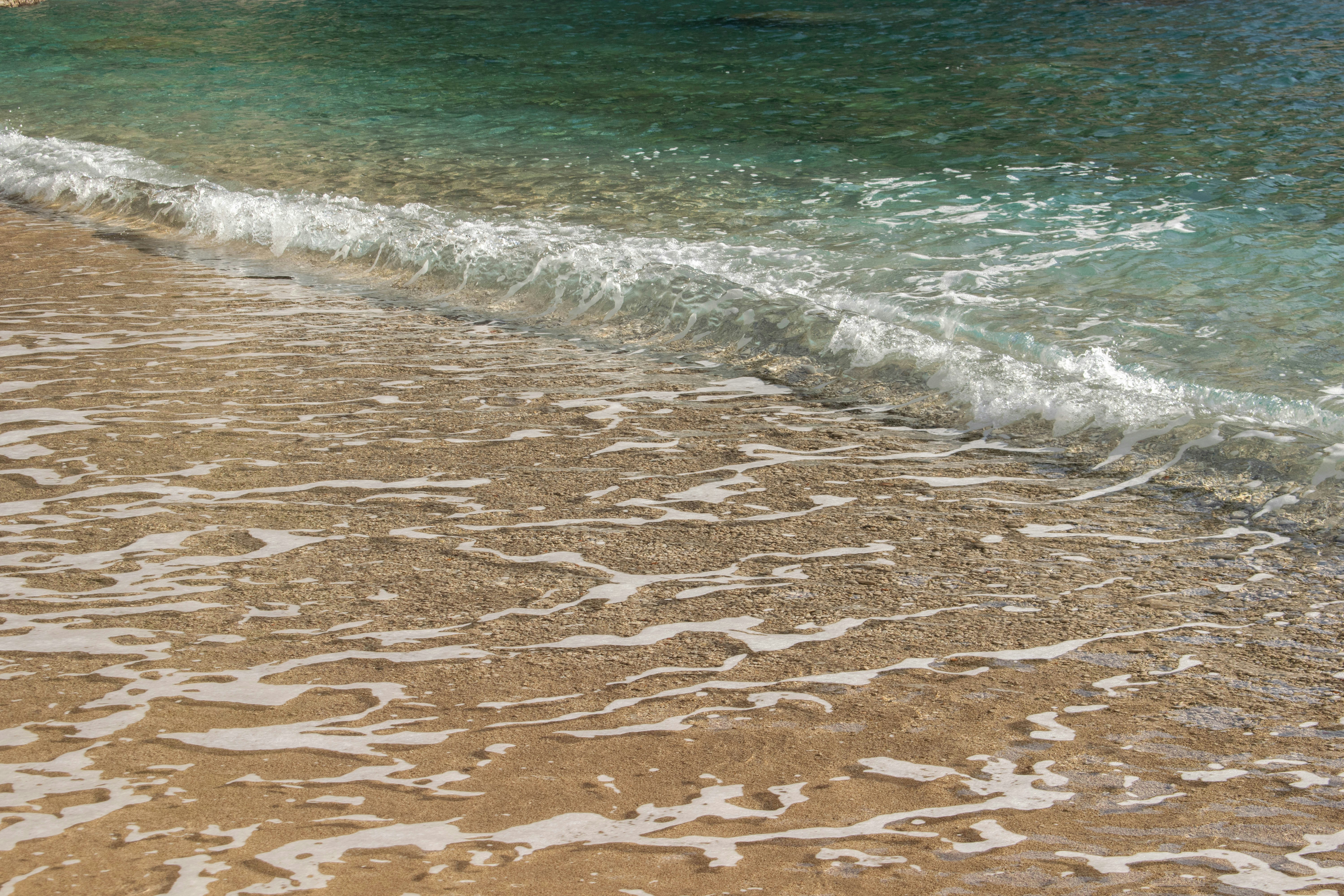 Nearshore Ripples: Sunlit Sand Meeting Turquoise Waves