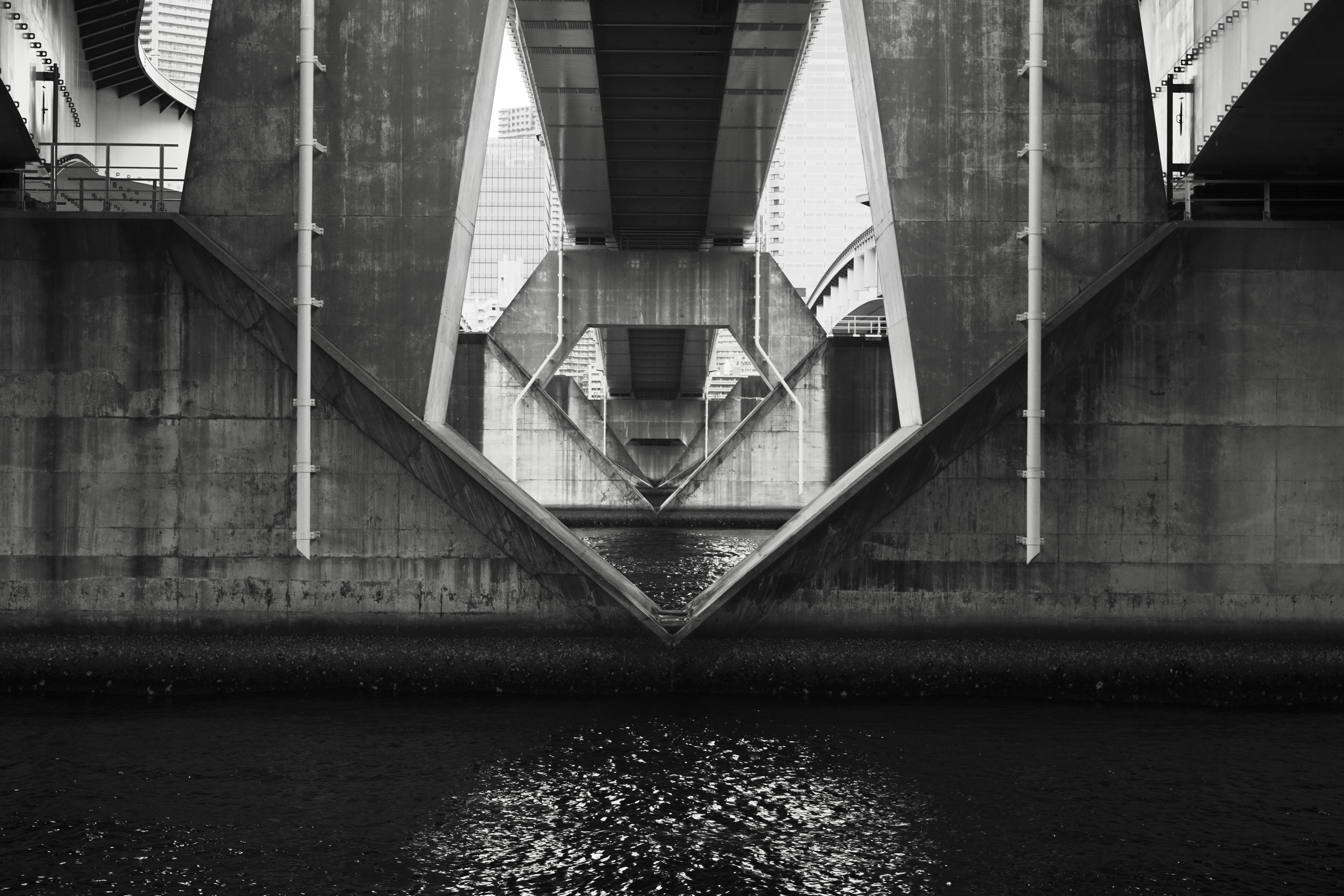Symmetry Under Concrete Arches: A Monochrome Riverside Confluence
