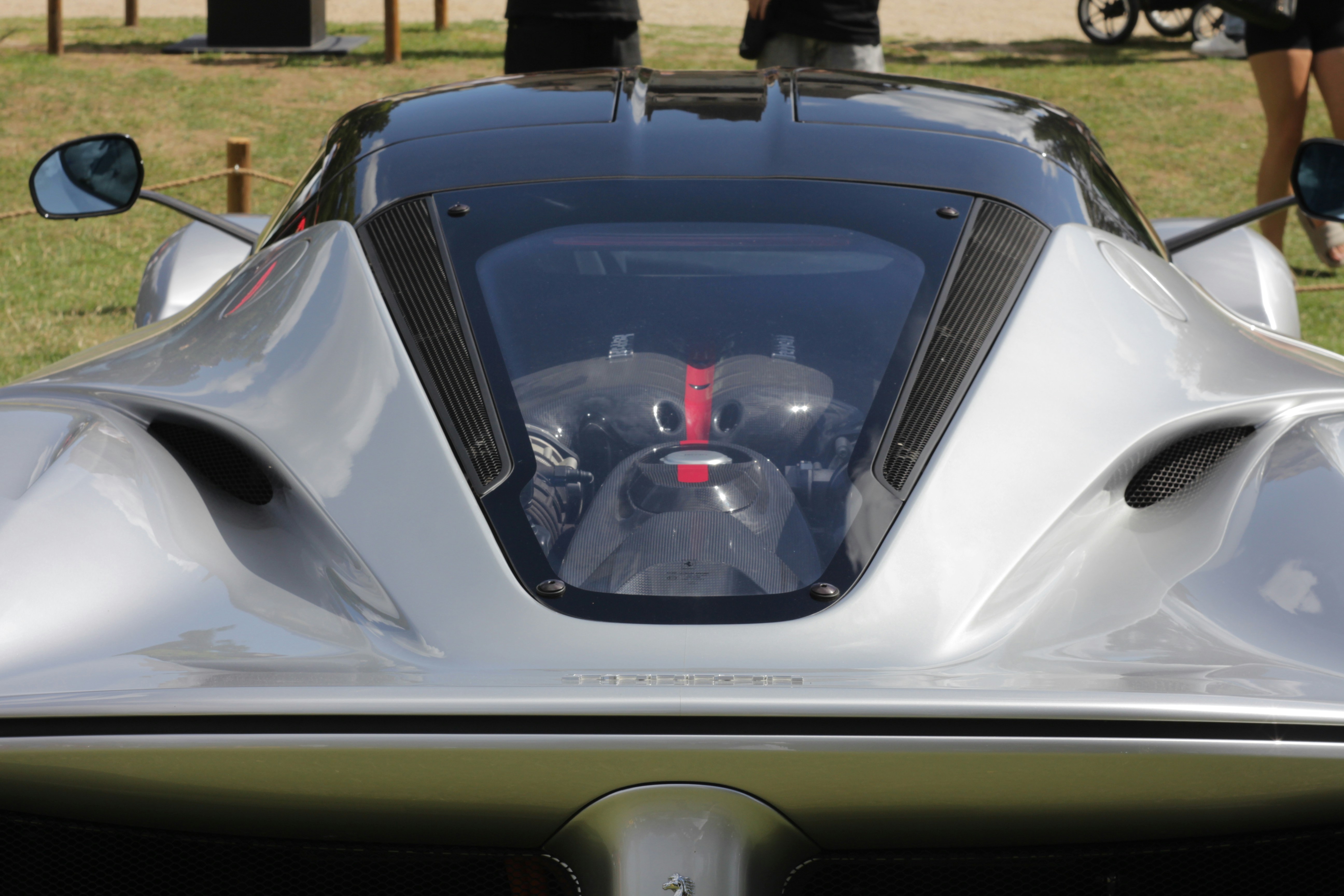 Sleek rear engine sports car cockpit visible through glass canopy, highlighting the mid-section engine bay and polished bodywork.