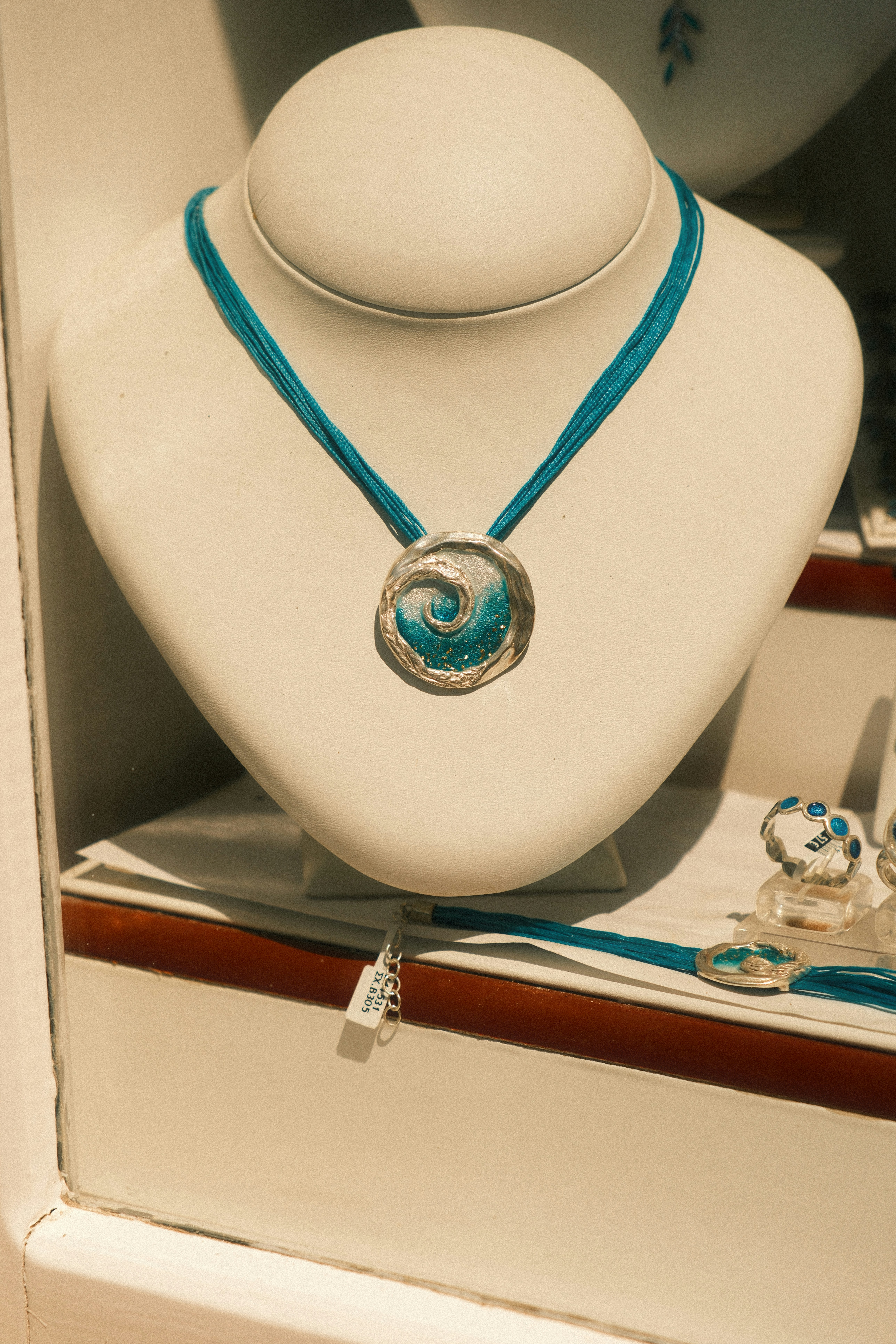 Turquoise pendant on a teal cord adorns a display necklace