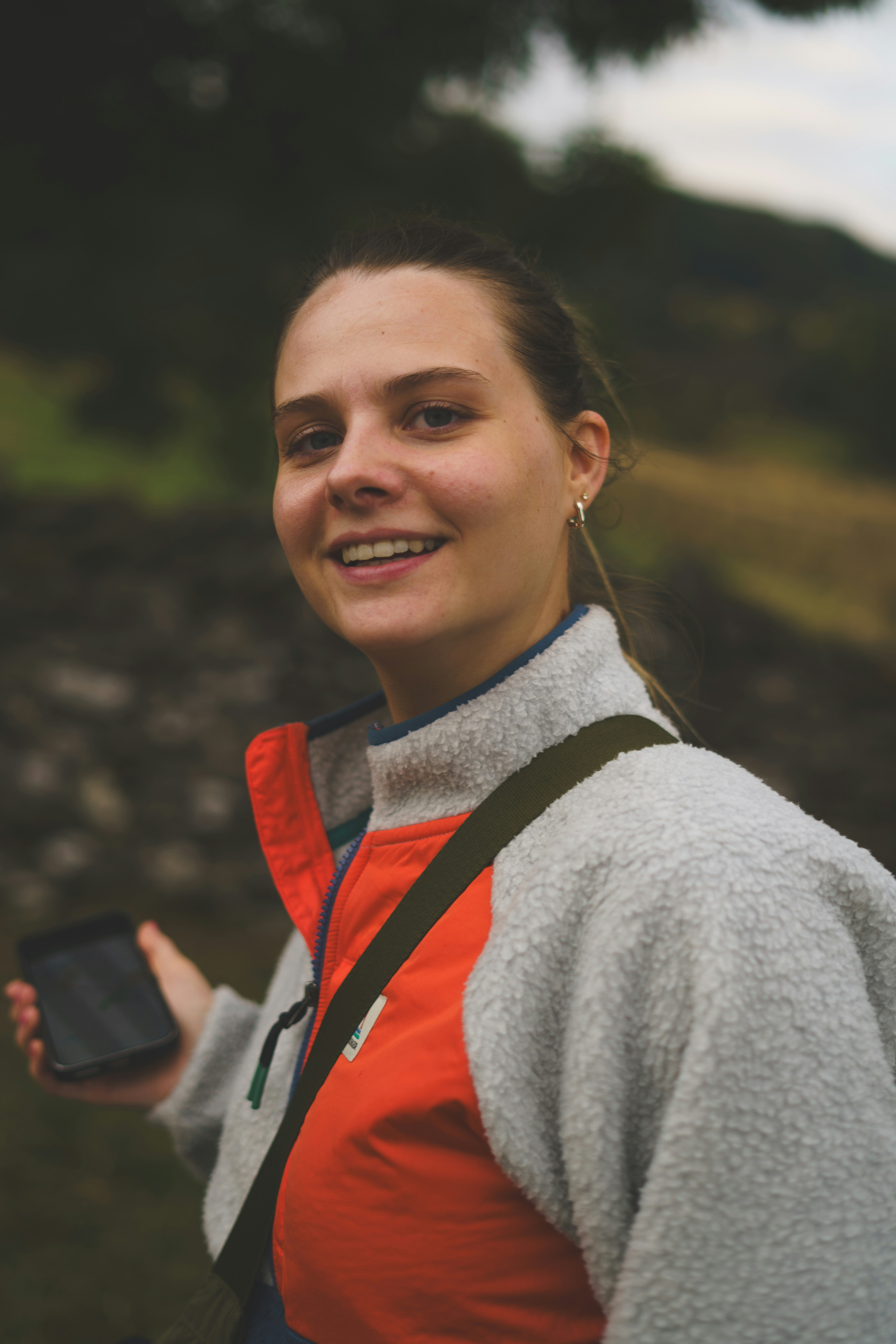 Smiling Explorer with Device in Hand on a Ridge