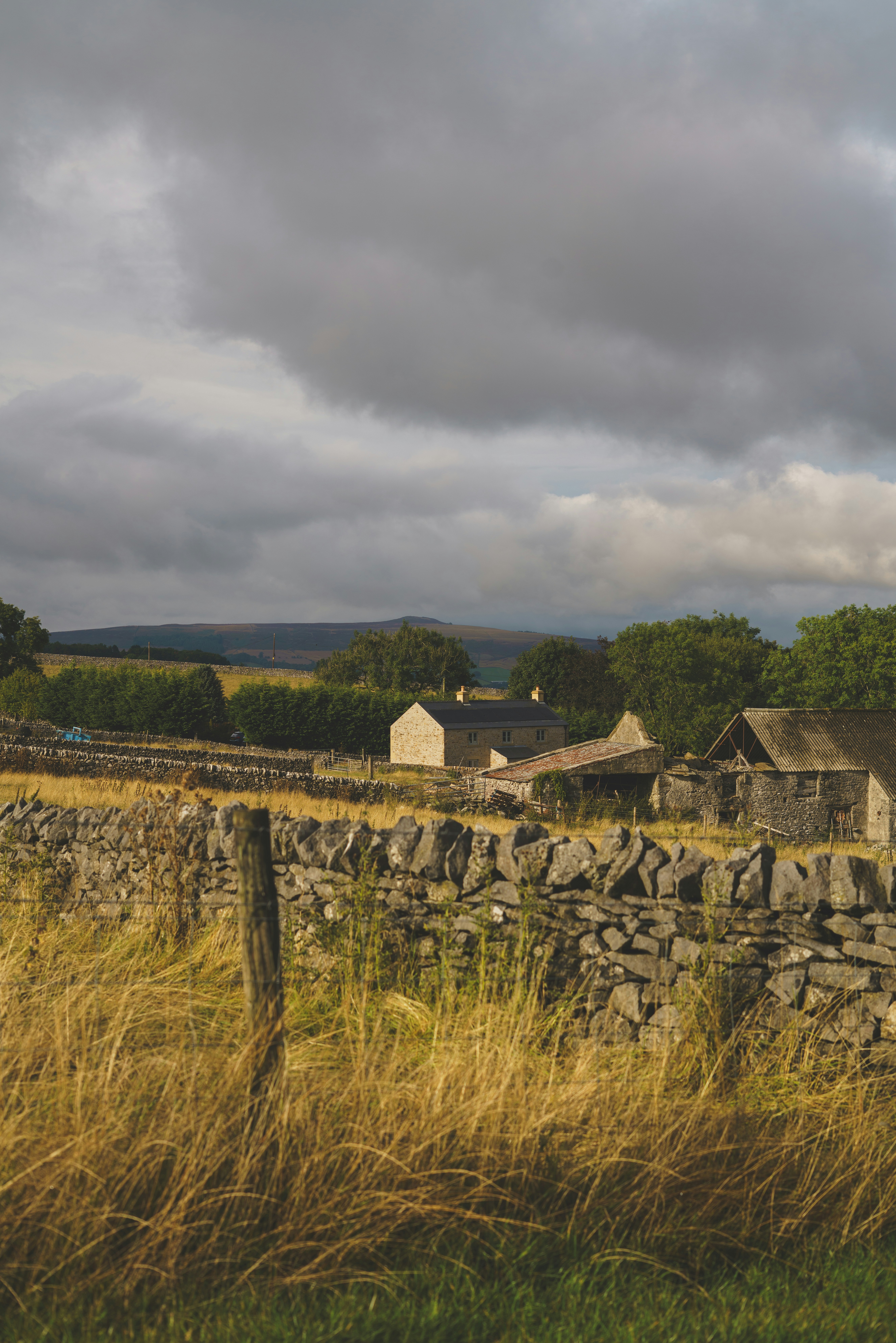 Stone Walls, Golden Field, and Quiet Village Under Cloudy Skies