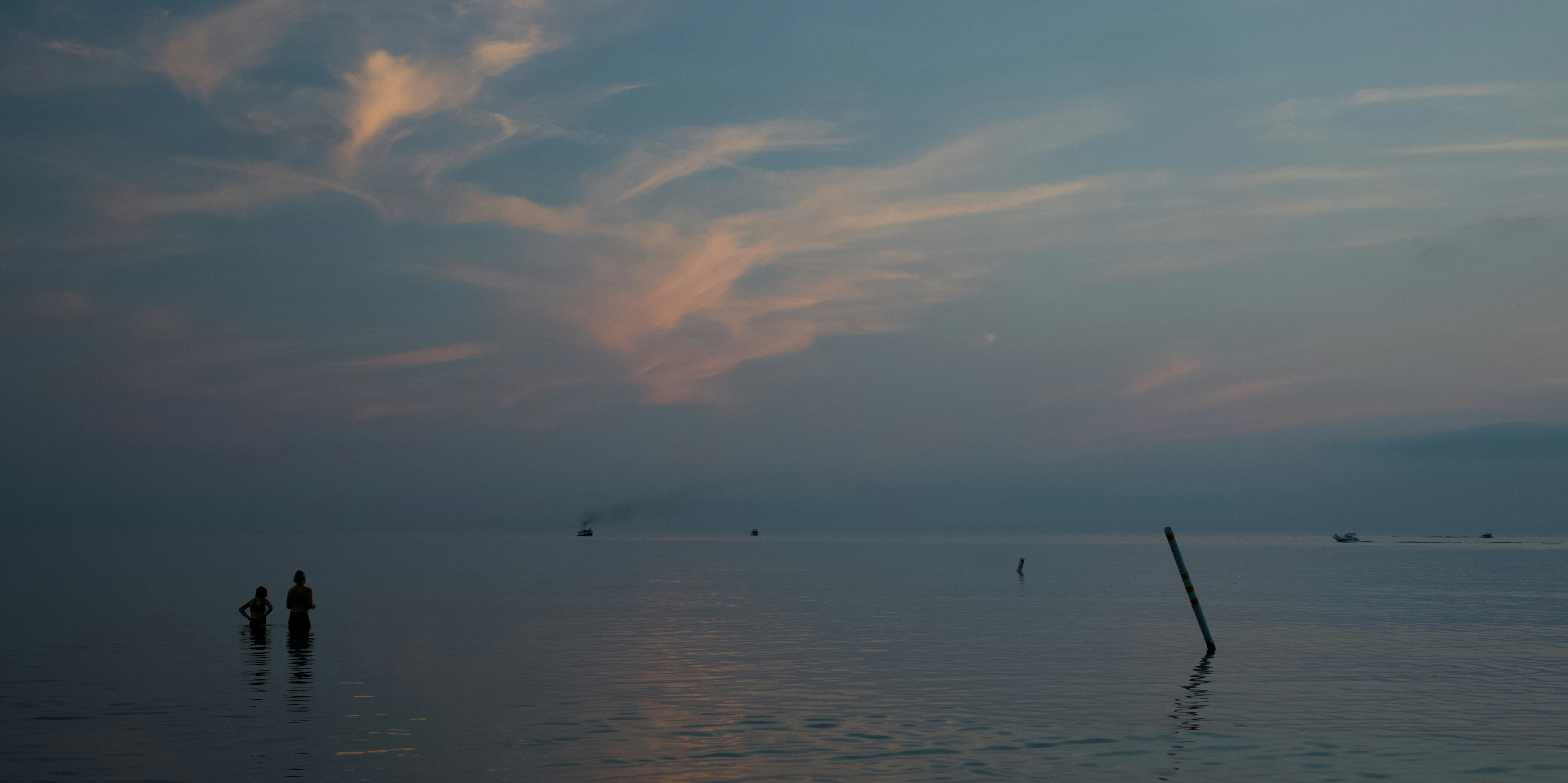 Quiet Horizon: Distant Figures at Dusk on a Calm Sea