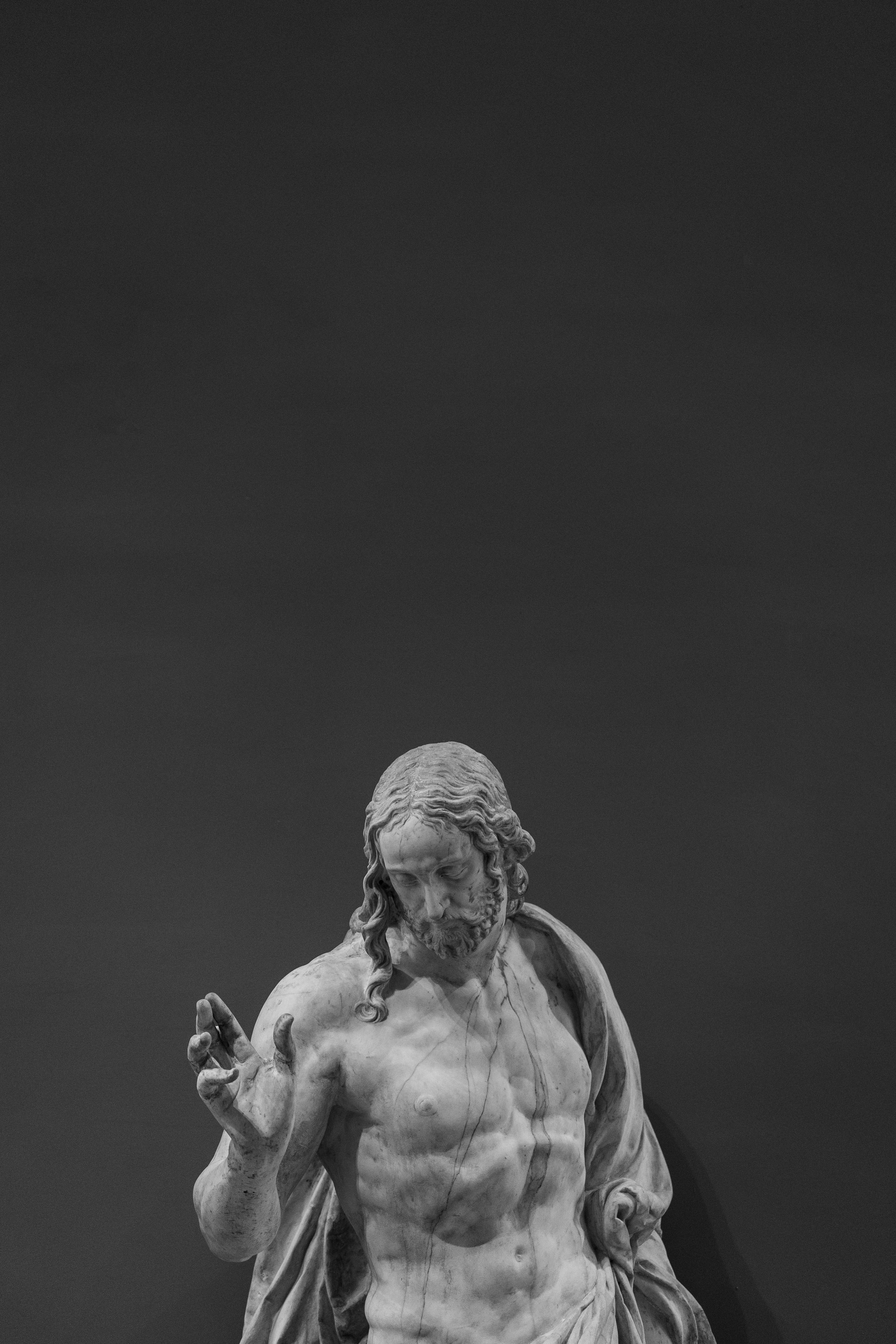 A marble statue of a bearded man with long hair gesturing with one hand