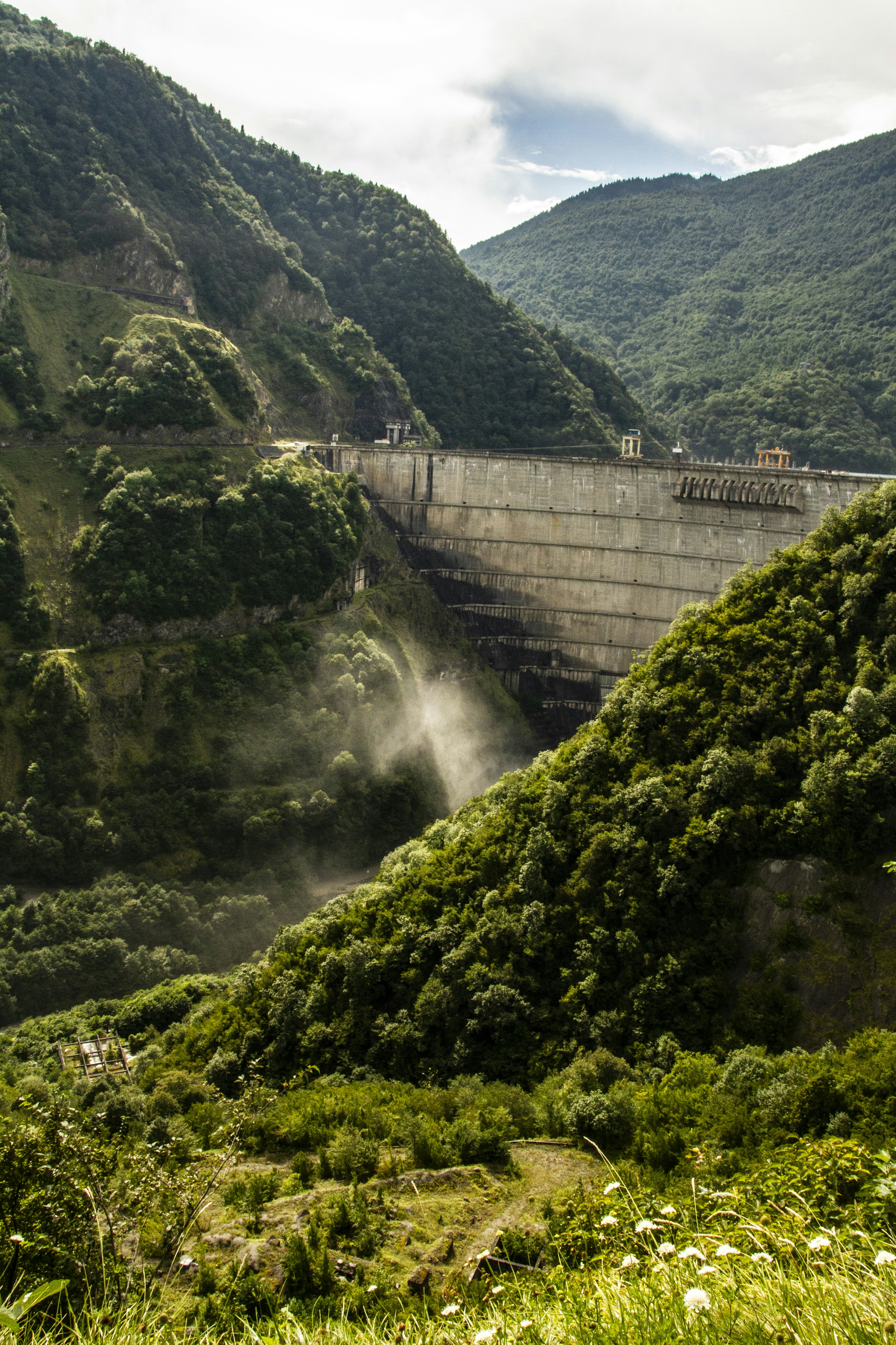 Cascade of Green Valleys and a Dam Crowned by Distant Peaks