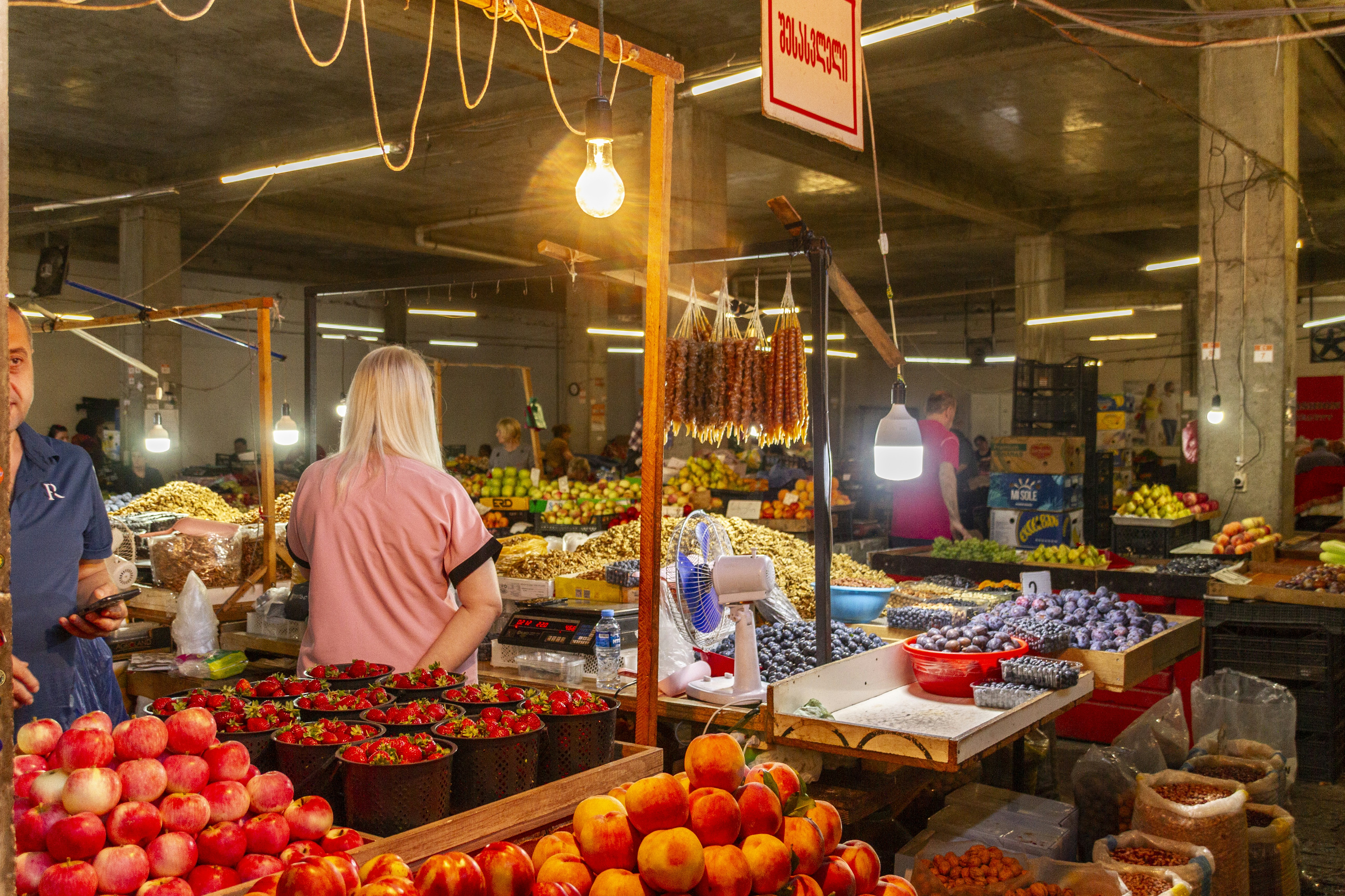 Market Stall Portrait: A Person in Pink Among Fresh Produce