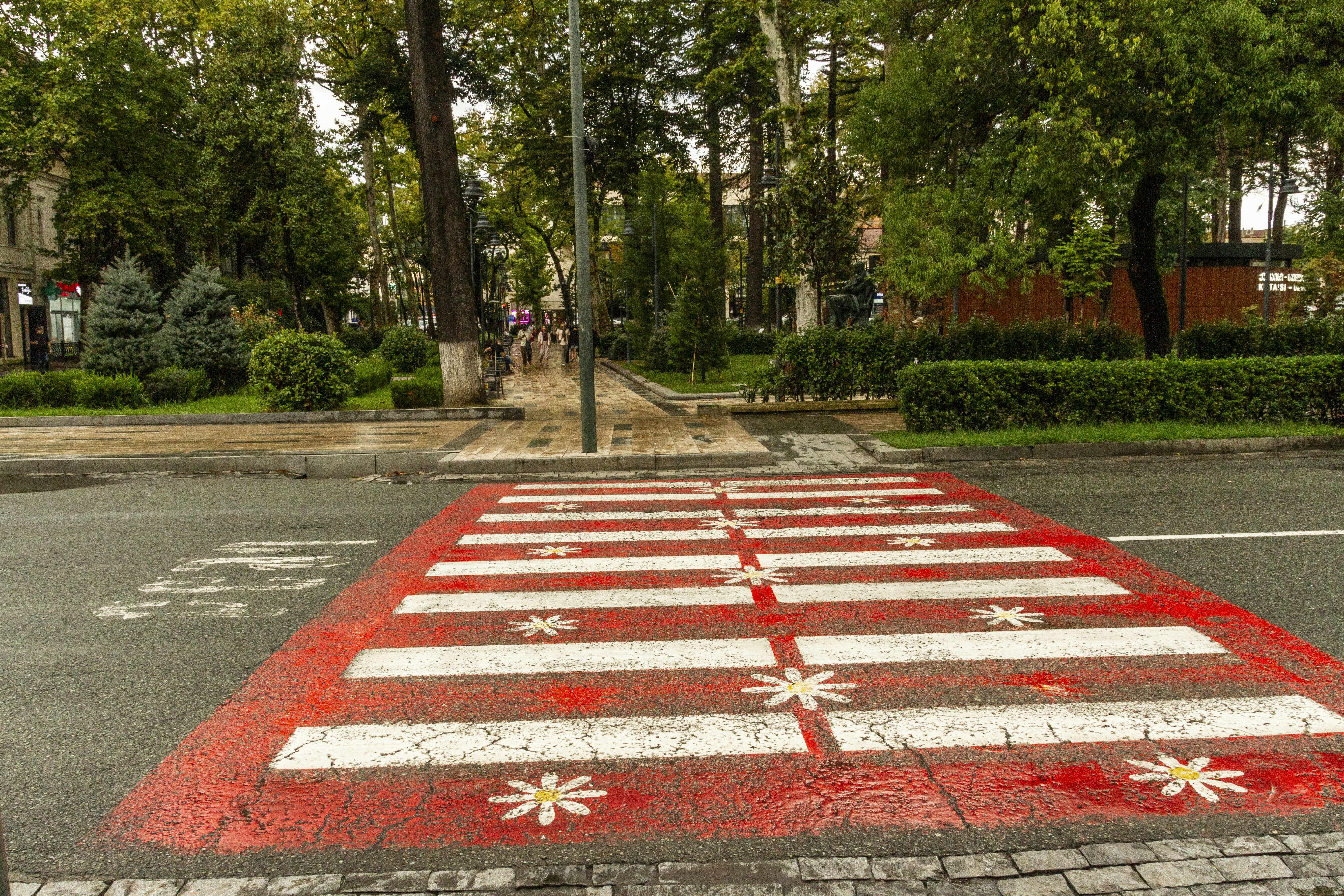 Red-and-White Pedestrian Crossing Roadway Fringed by a Green Park