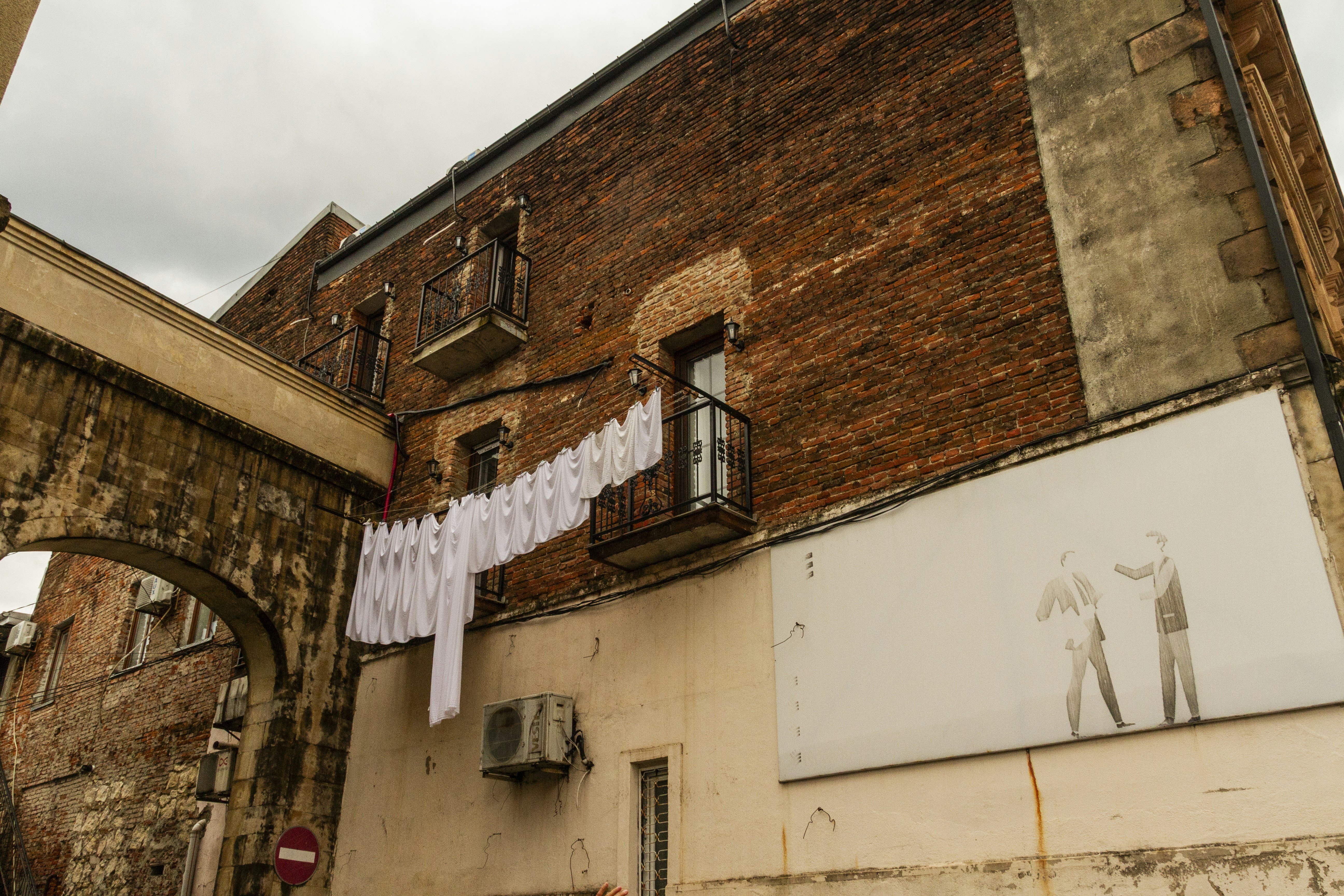Brick Facade, Laundry, and Mural: A Quiet Urban Scene
