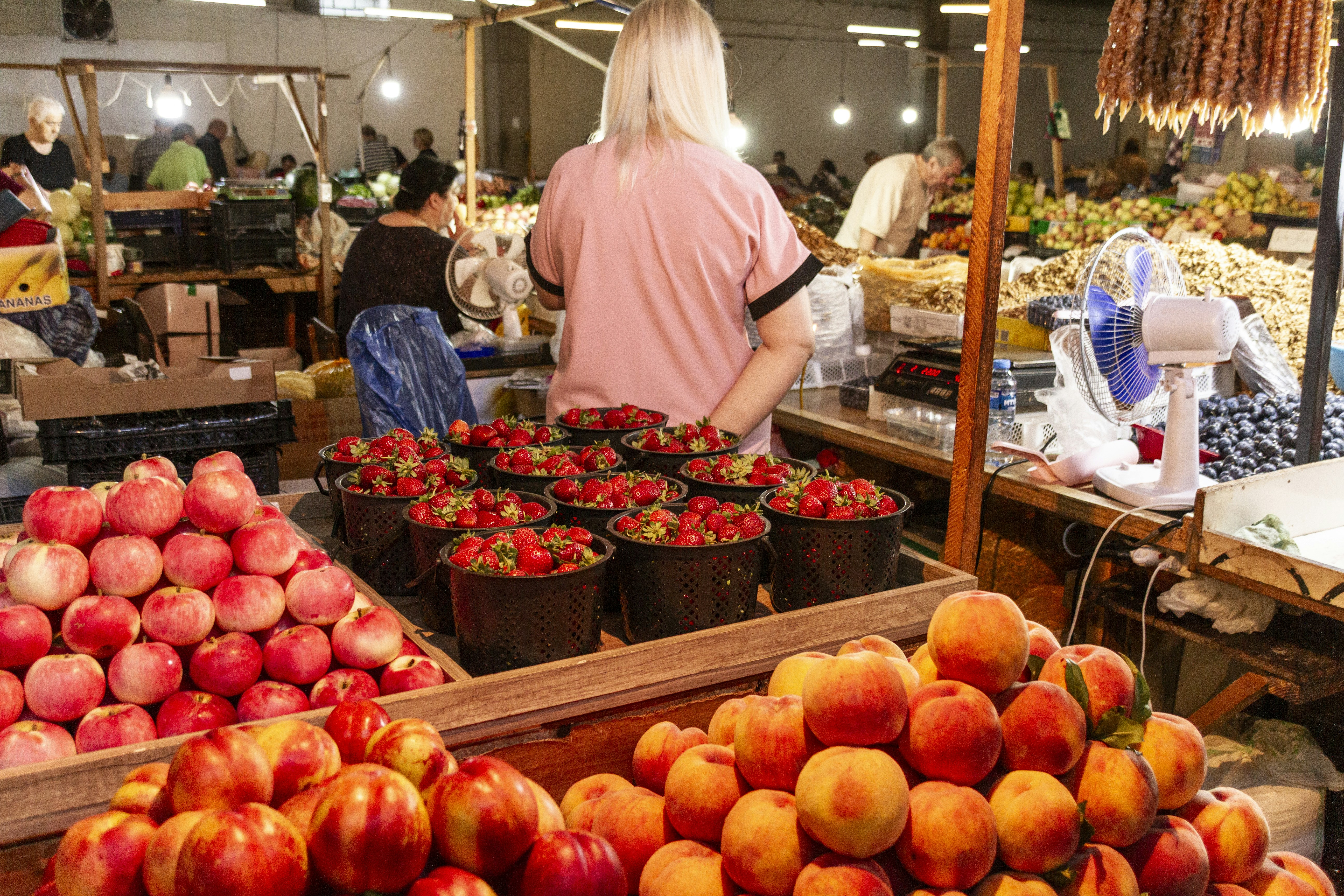 Market Scene: Fresh Reds and Golden Oranges Framing a Woman in Pink